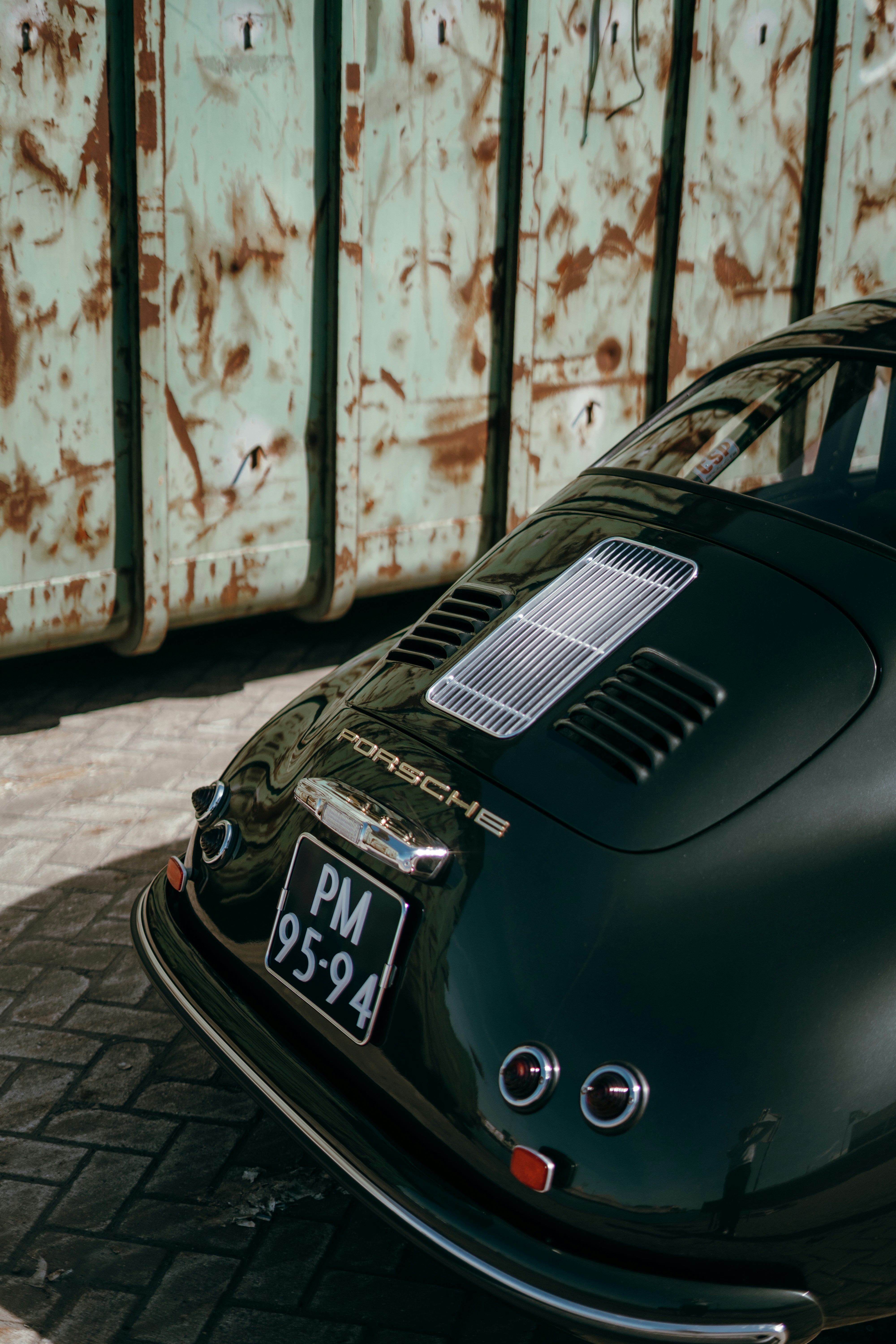 Tail of an Icon: Green Porsche Resting by Weathered Gates