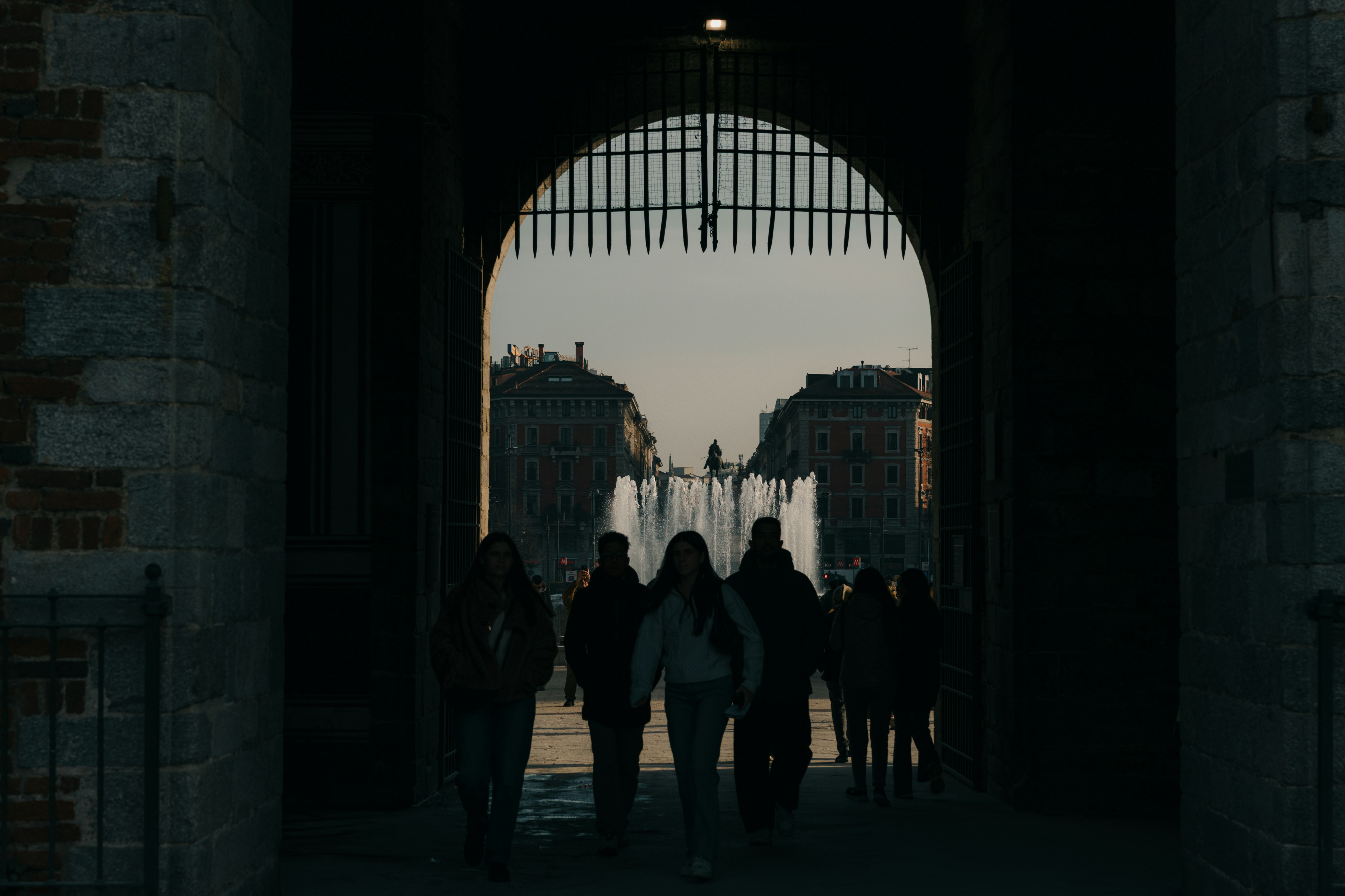 Archway Portrait: silhouetted group stepping into daylight