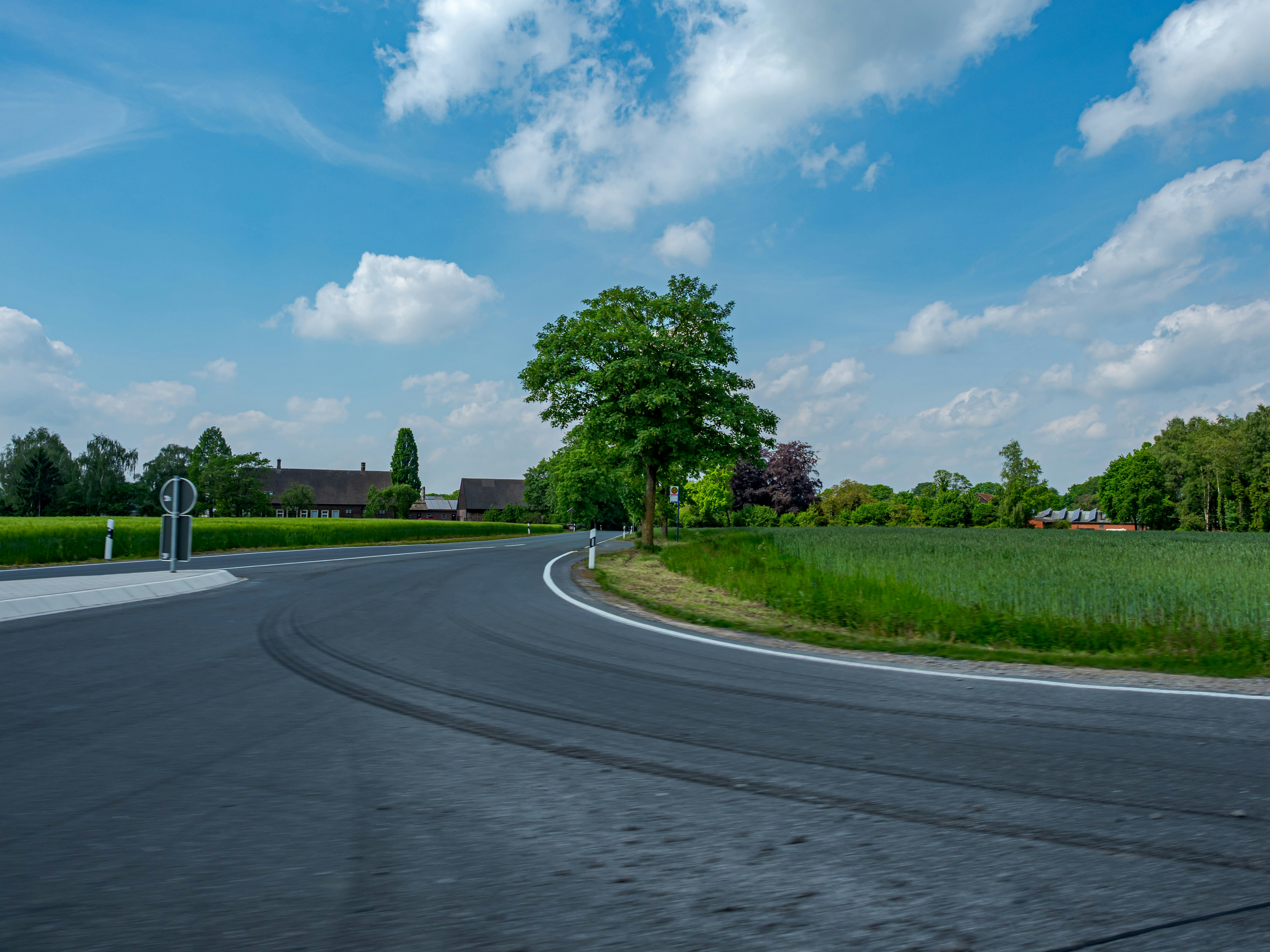 Curve of asphalt and green fields under a blue sky