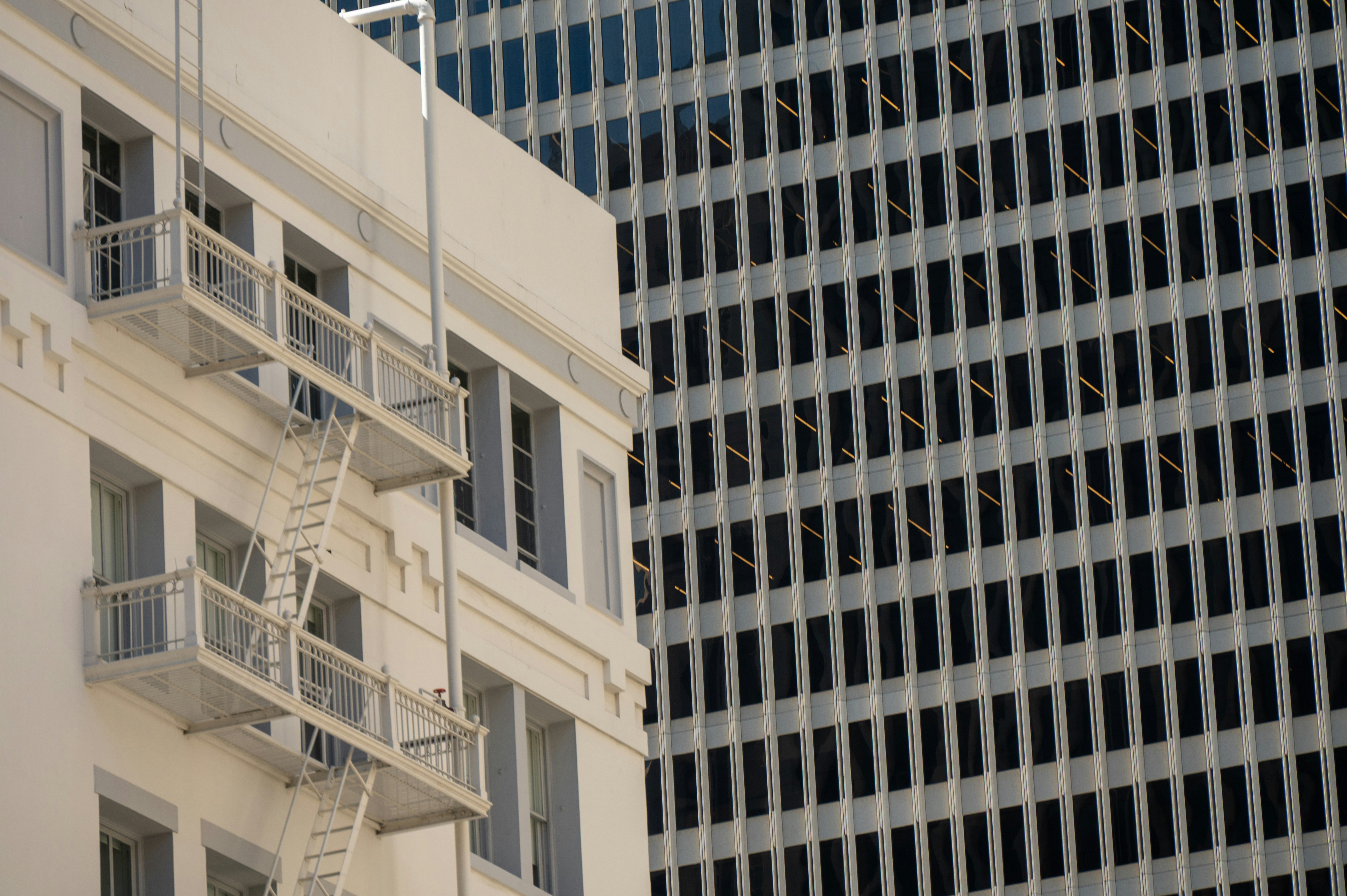 Contrasting Facades: Fire Escape Lines Beside Modern Grids