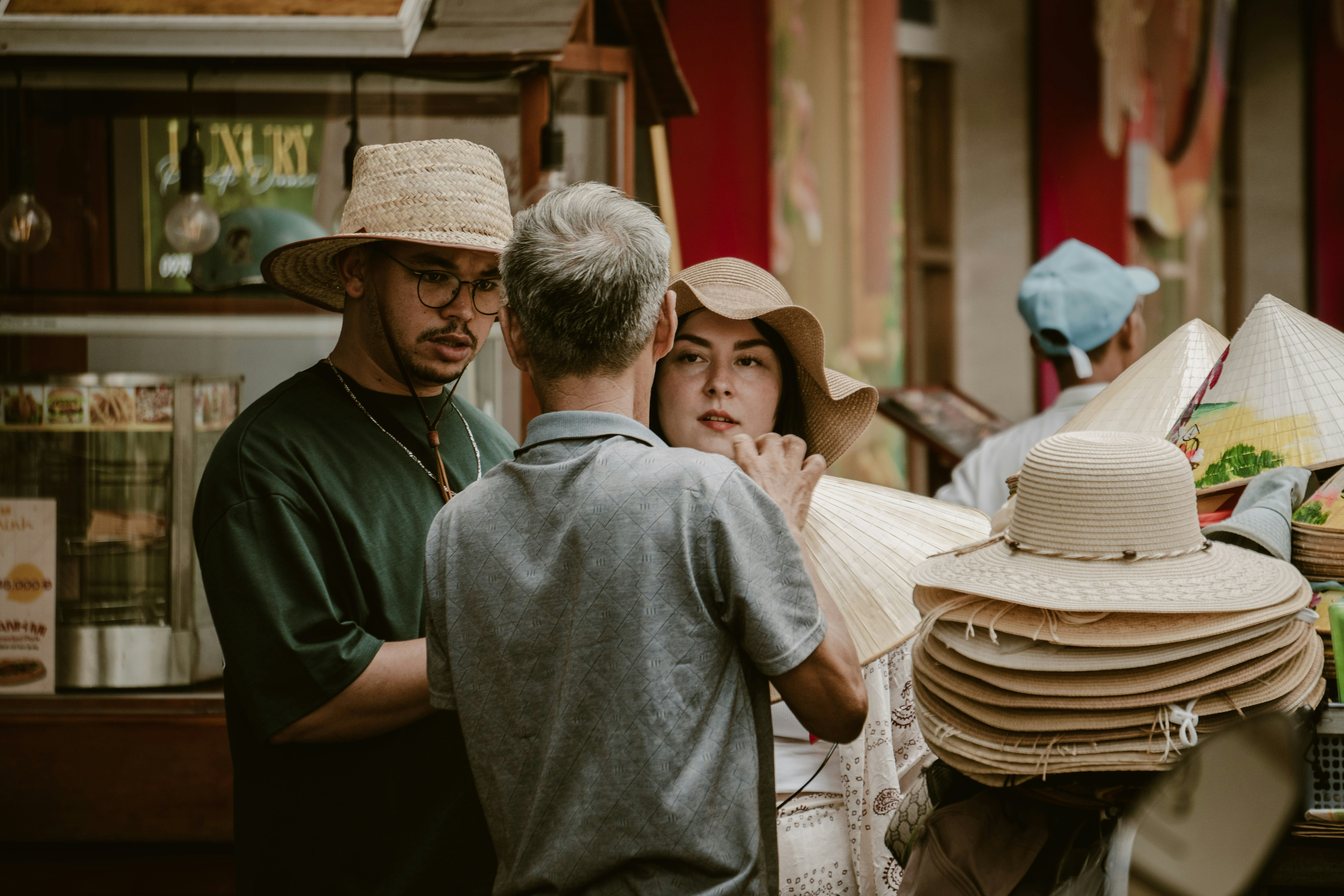 Conversation under straw hats in a sunlit market stall