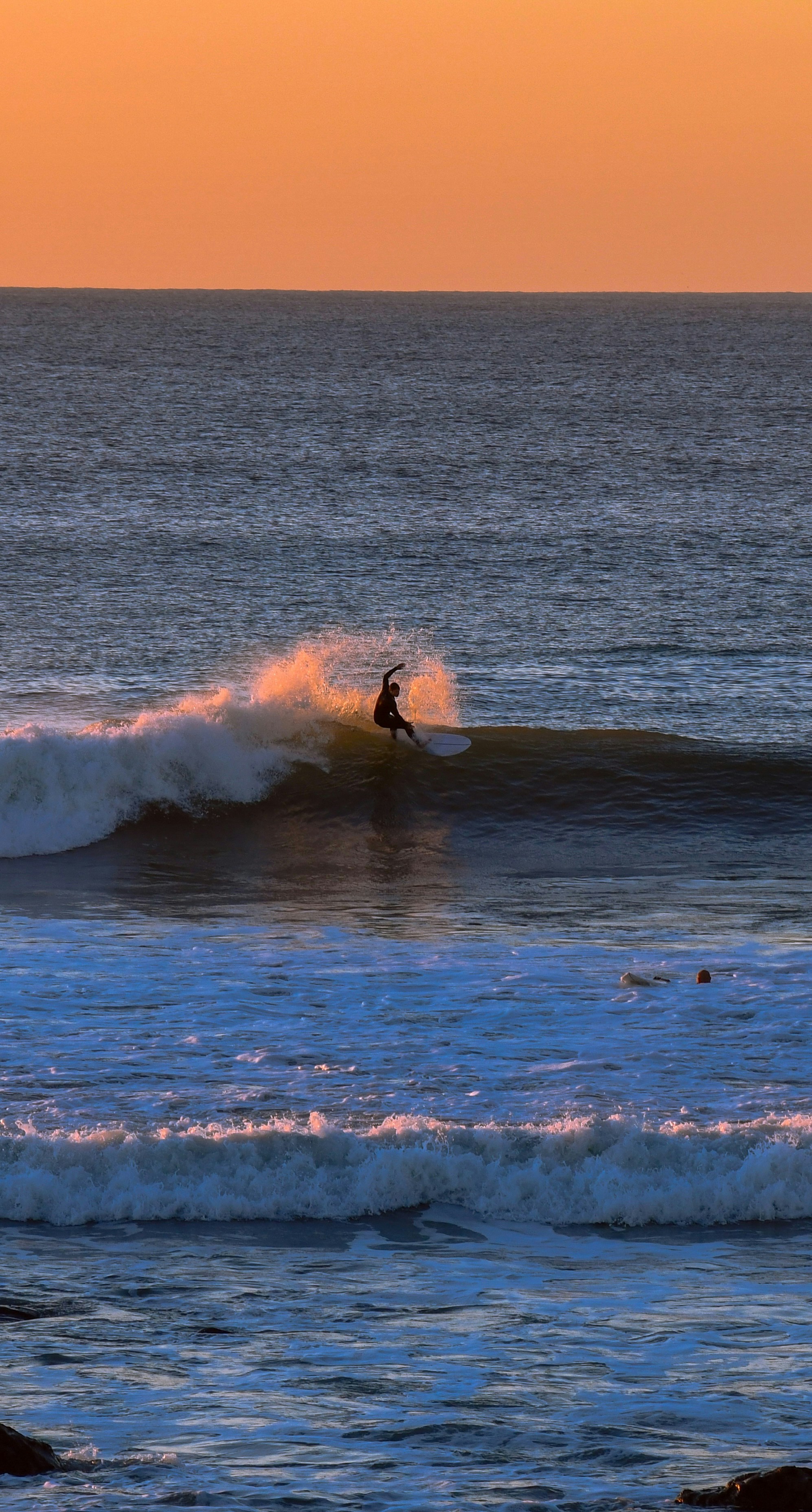 Sunset Surf: A Lone Surfer Carves Through a Sky-Glow Wave