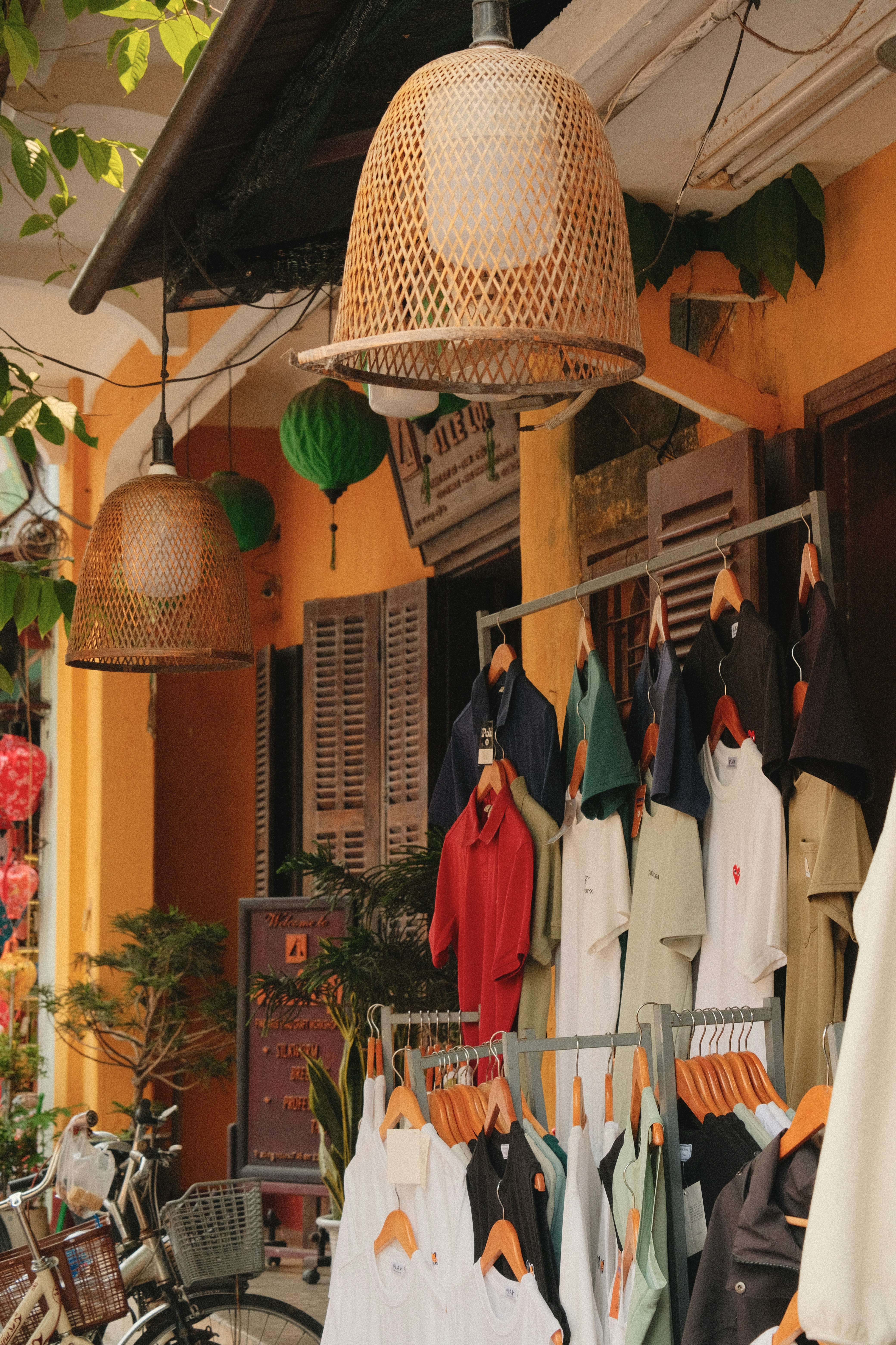 Sunlit Streetwear Bazaar: Colorful Shirts on Display under Woven Canopies