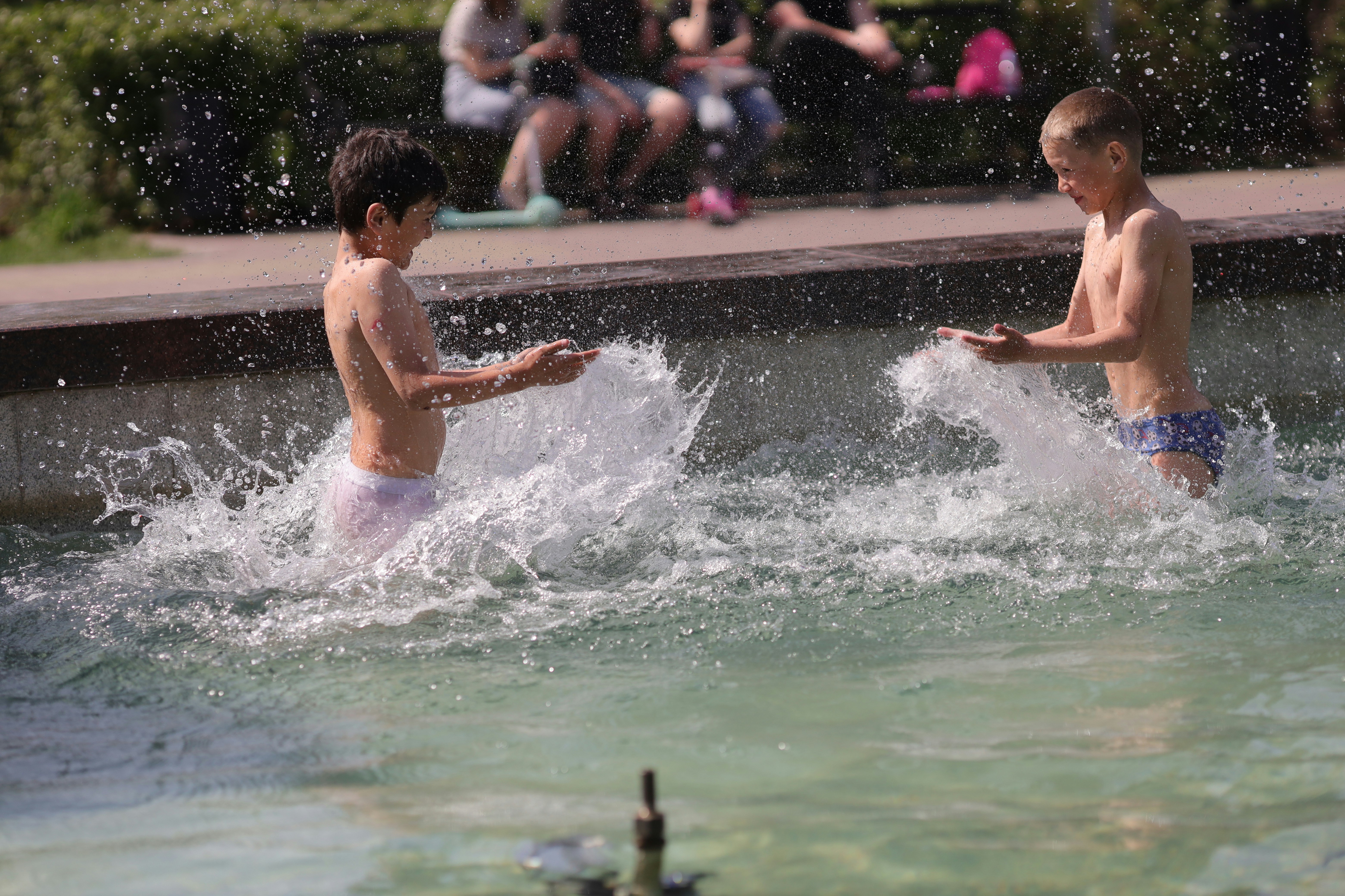 Splash duel: two boys chase the spray in a sunlit pool