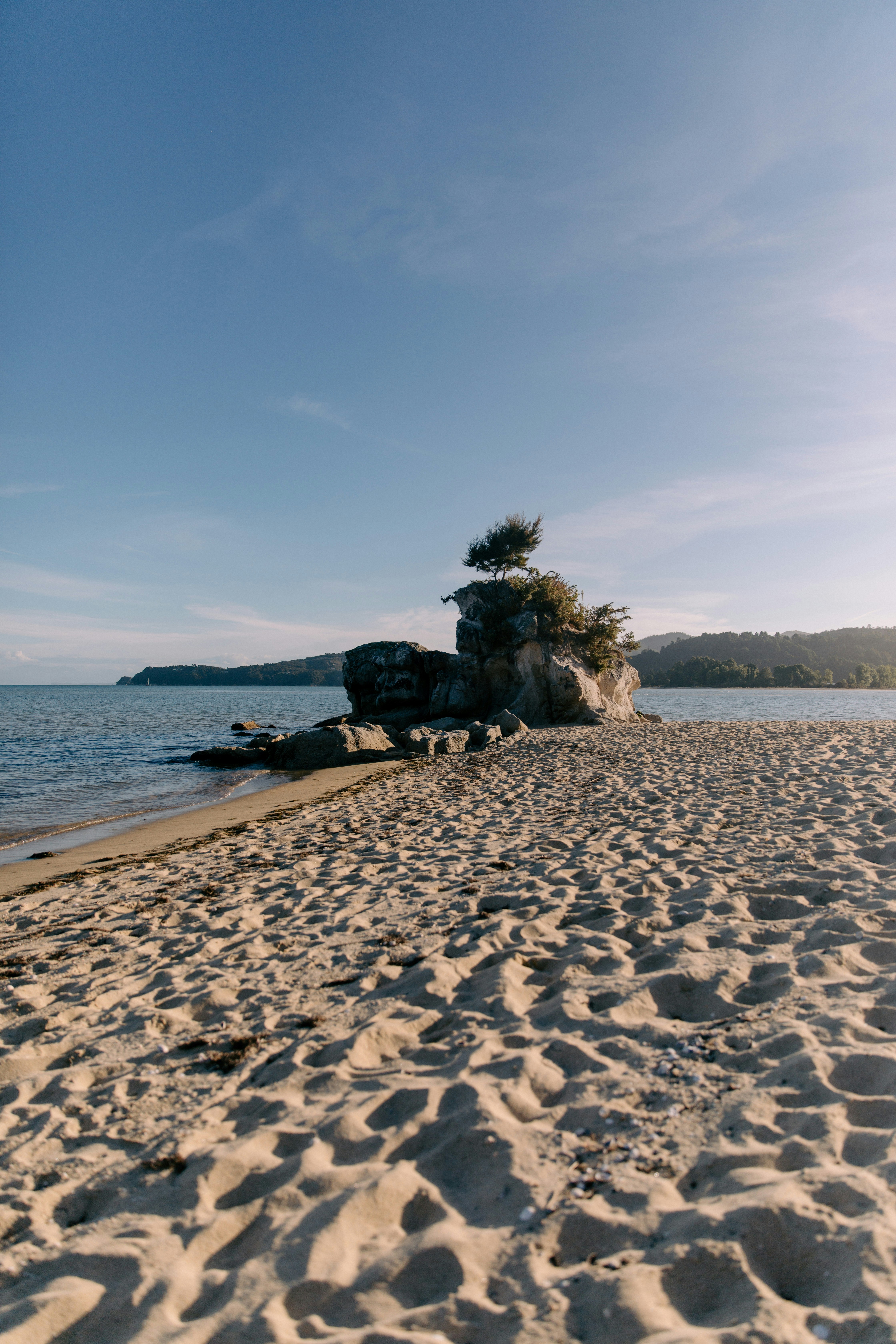 Sunlit Rock Sentinel Piercing the Quiet Shore