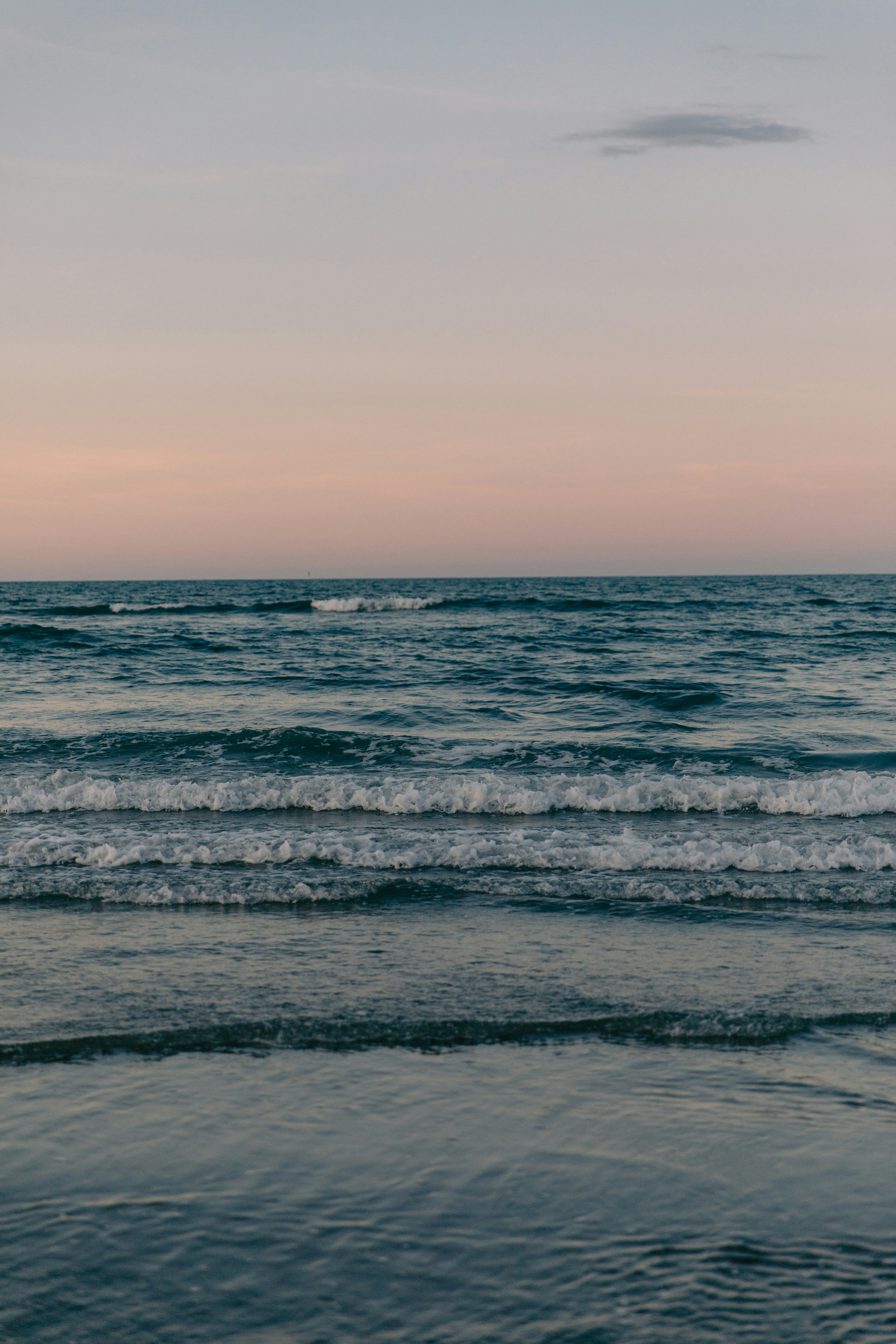 Dusk at the Calm Ocean: Gentle Waves Under a Soft Coral Sky