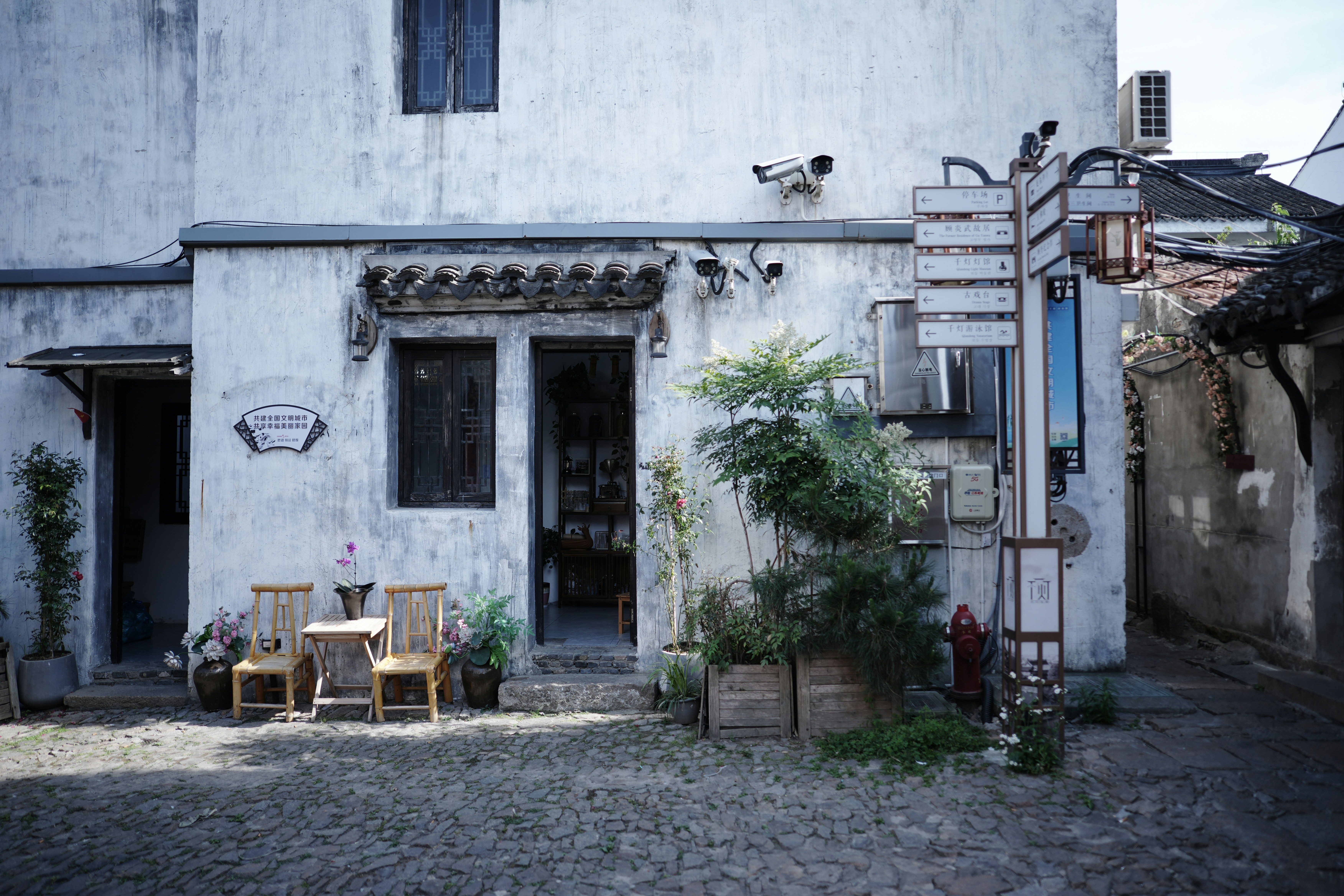 Quiet Courtyard Café Facade with Flower Pots and Signpost