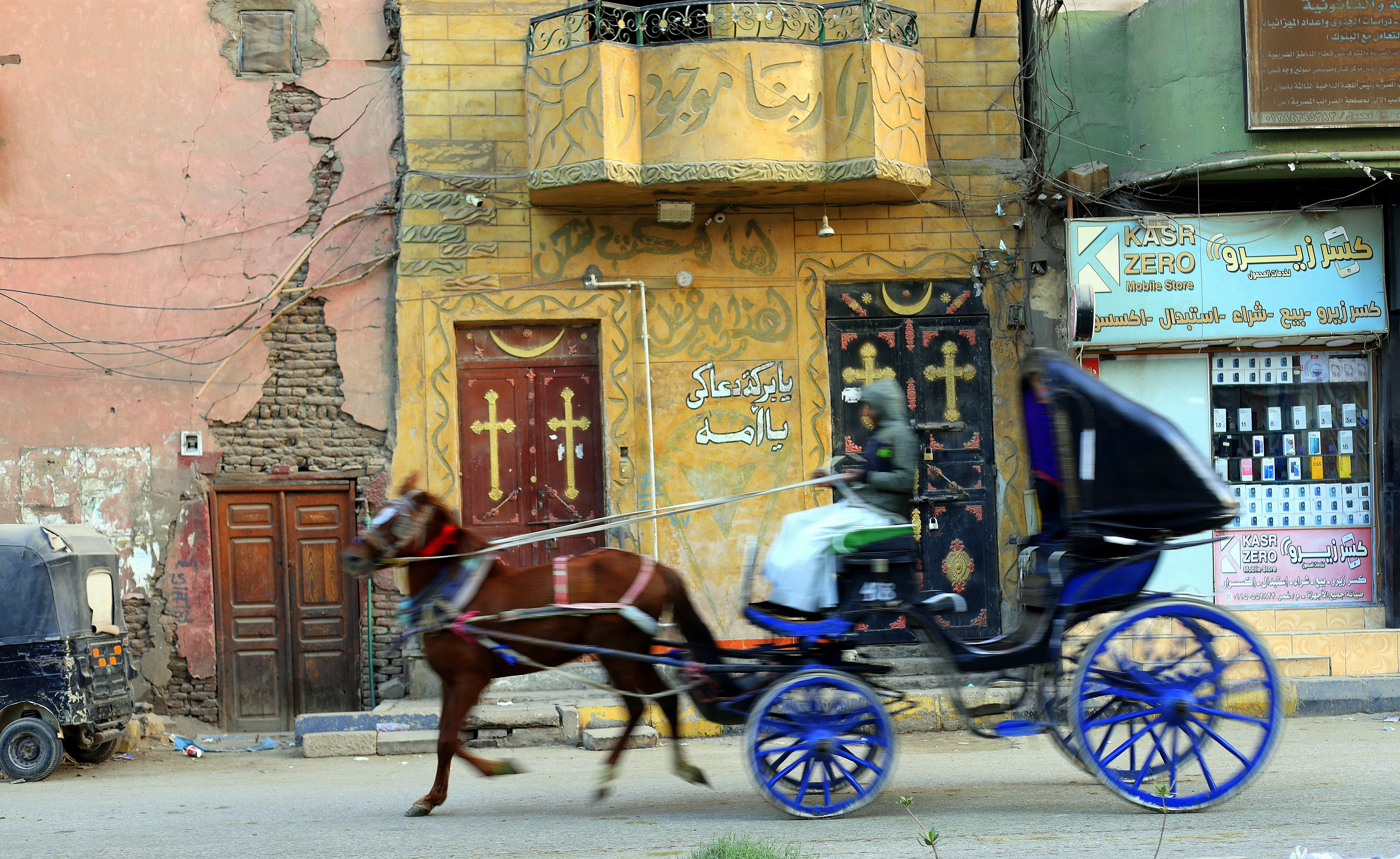 Blue-Wheeled Carriage in Motion Past a Colorful Facade