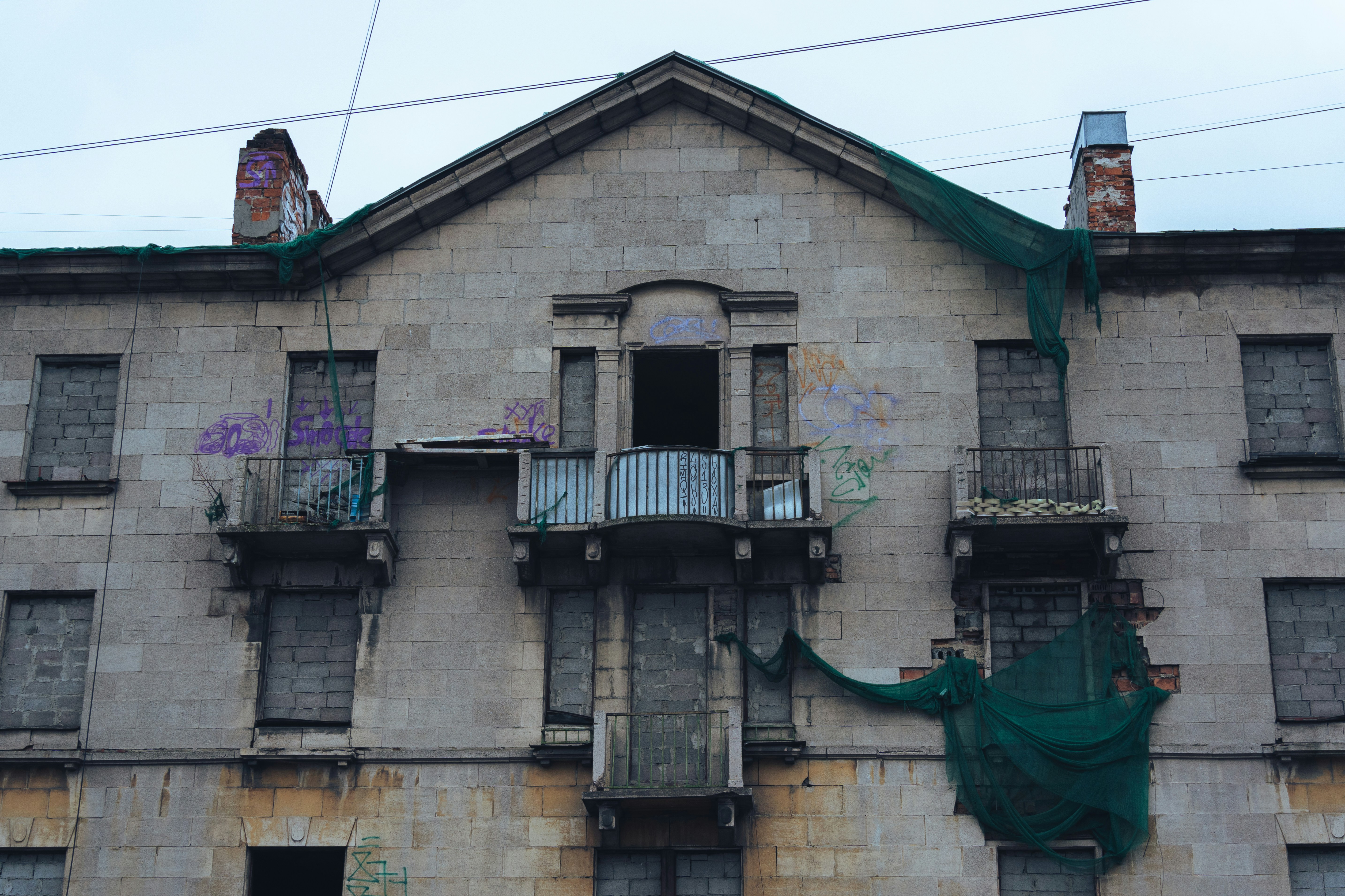 Weakened Facade of an Abandoned Mansion with Tattered Netting