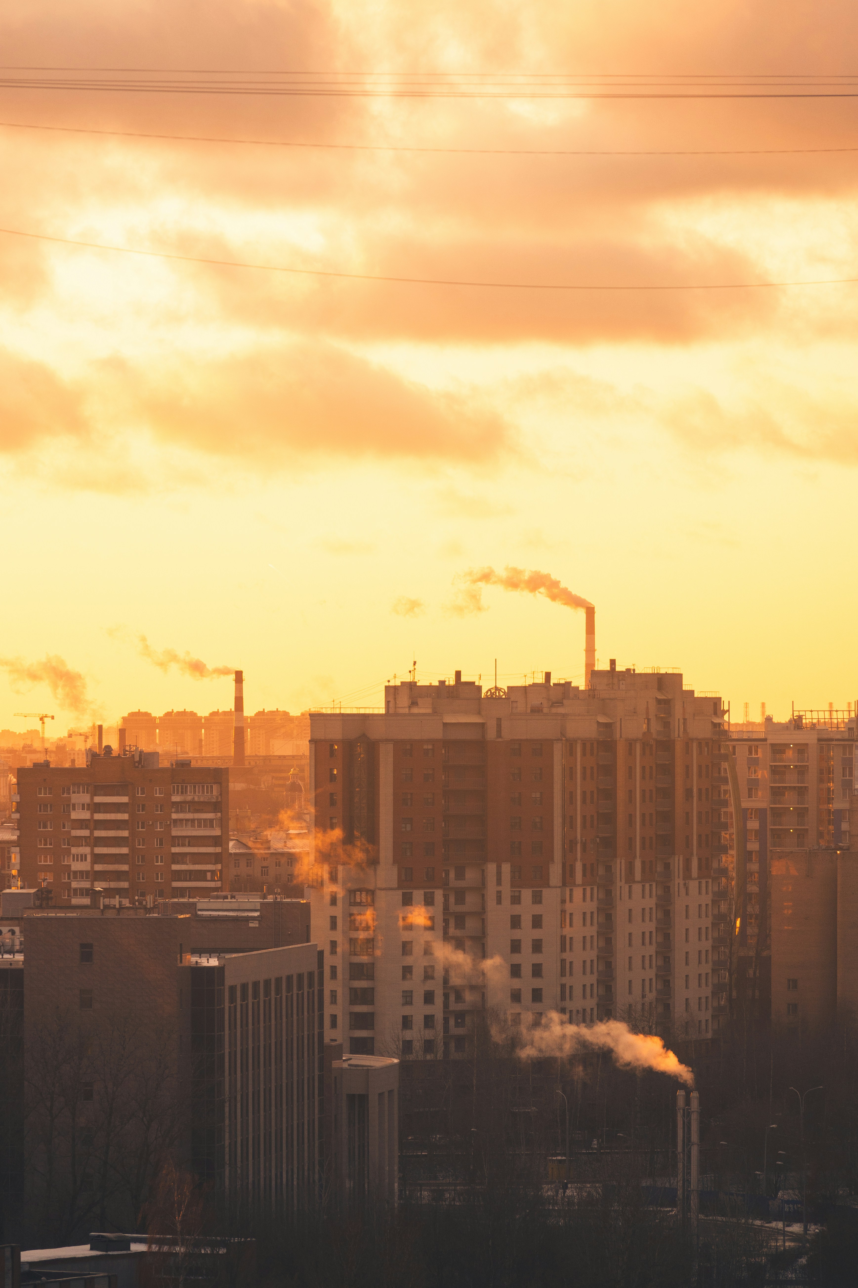 Golden Exhaust: Urban sunset over smokestack skyline