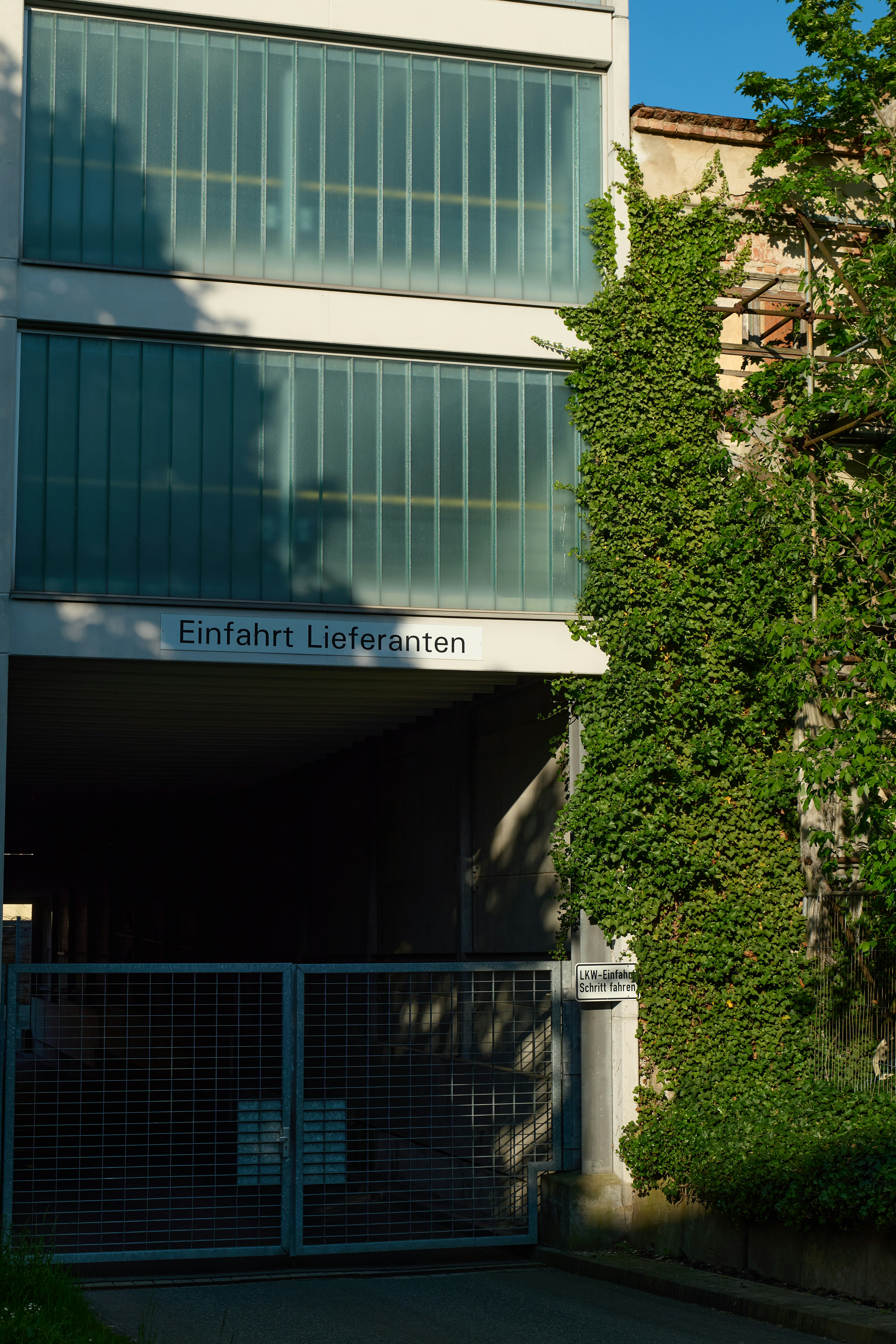 Concrete building with ribbed windows, suppliers entrance, and green ...