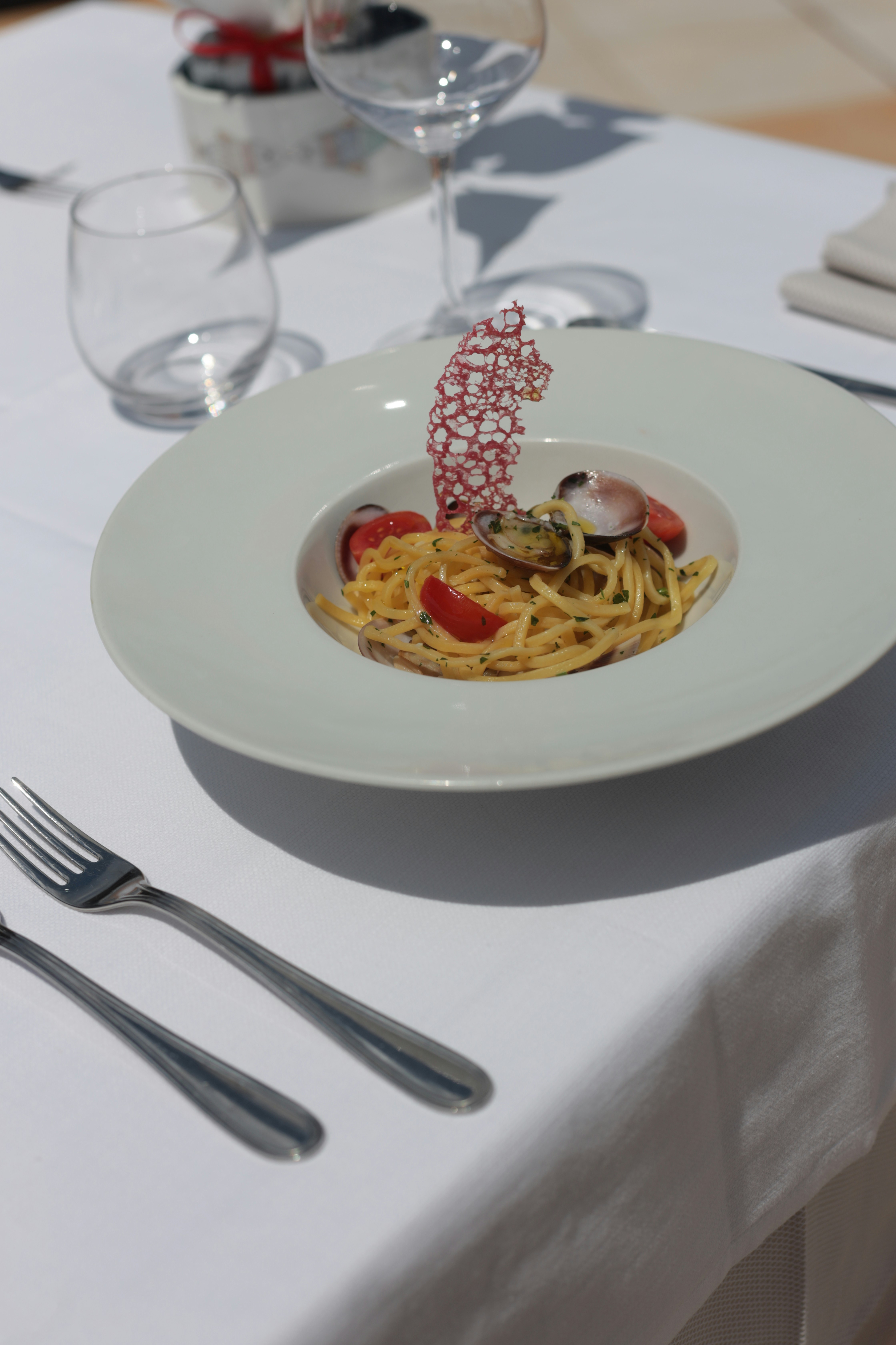 Plate of delicate pasta with a ruby décor snowing the scene across a refined table