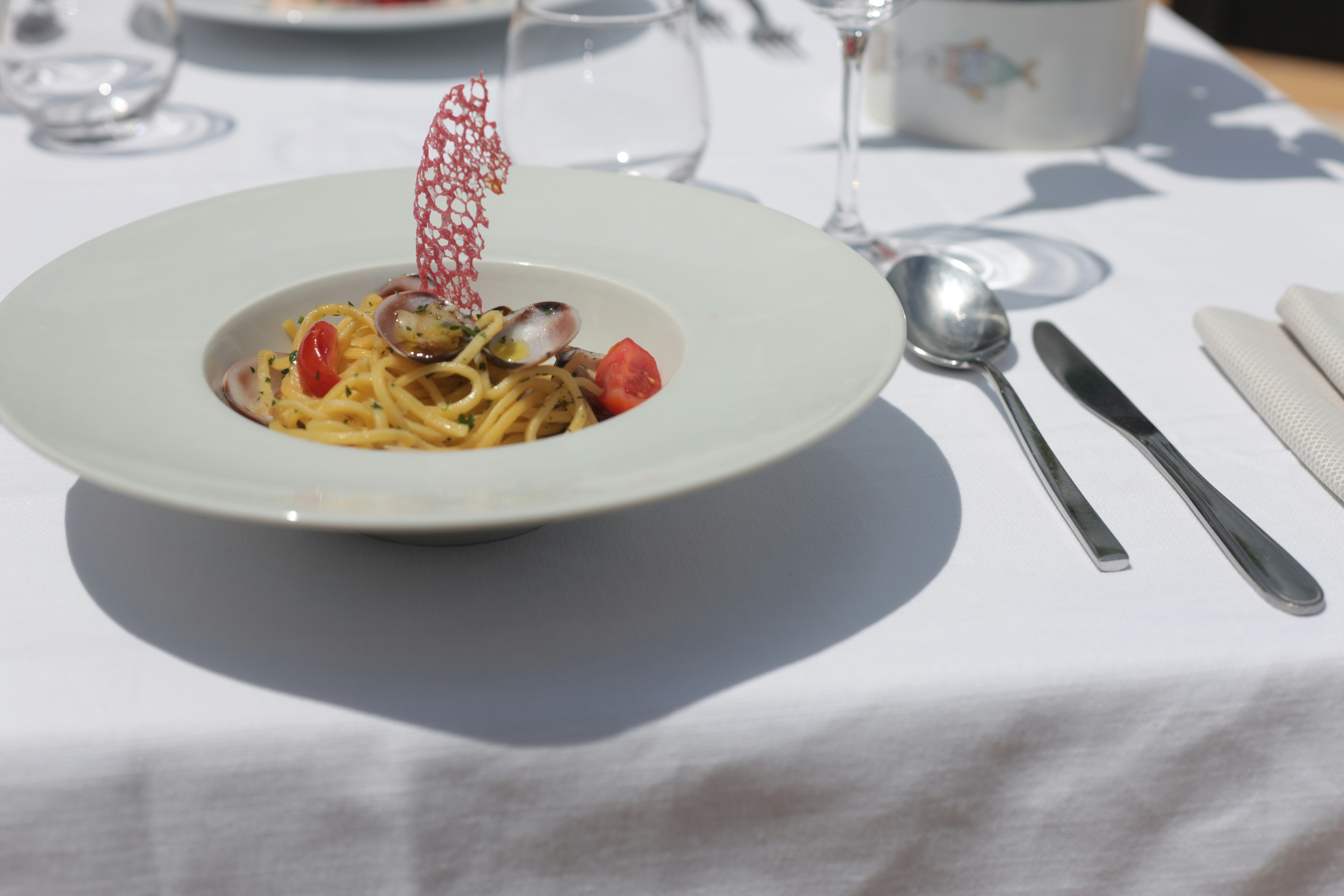 Plate of delicate pasta with a lacy garnish on a sunlit banquet table