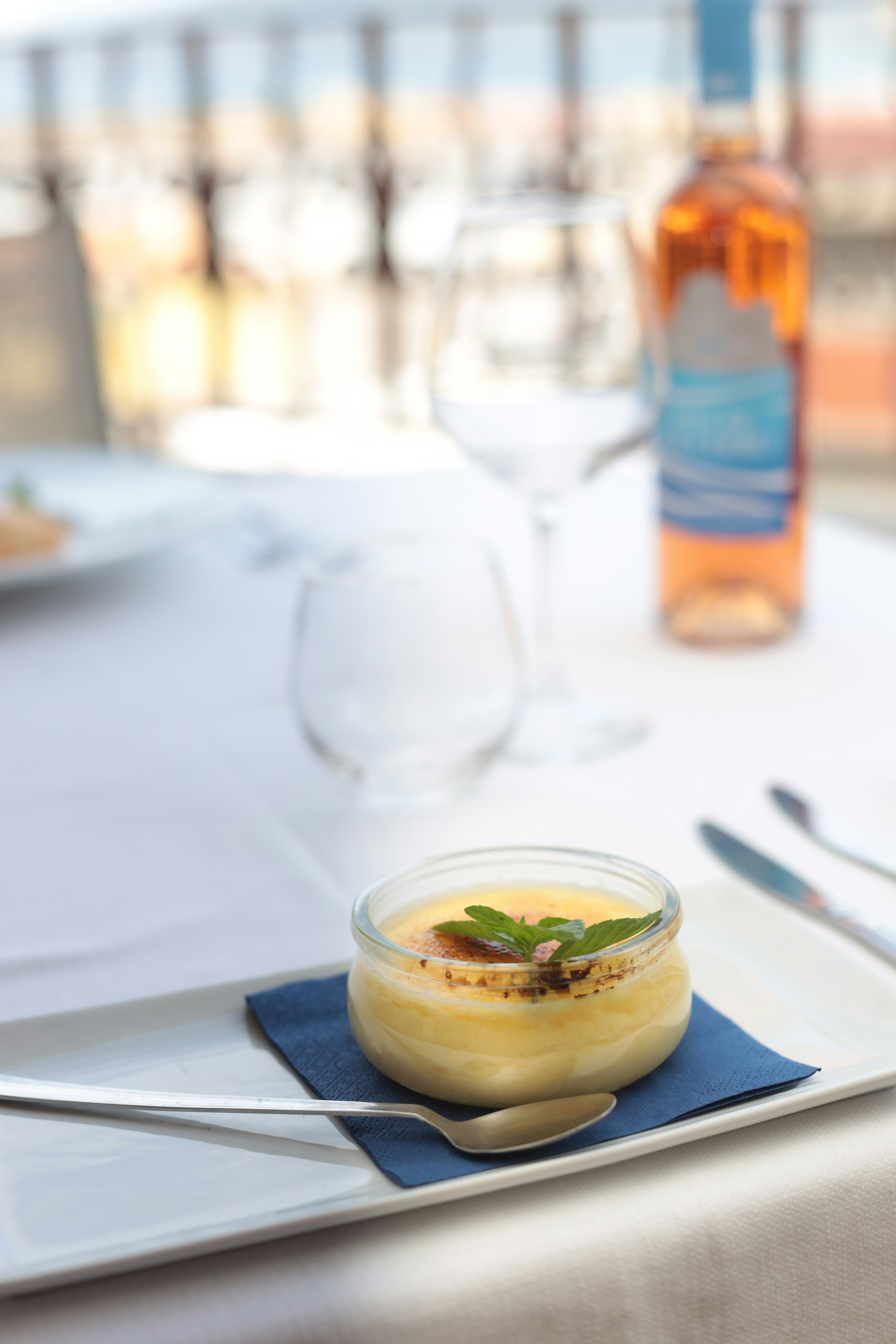 Creamy Dessert in a Glass on a Dinner Table with Glowing Bottle Backdrop