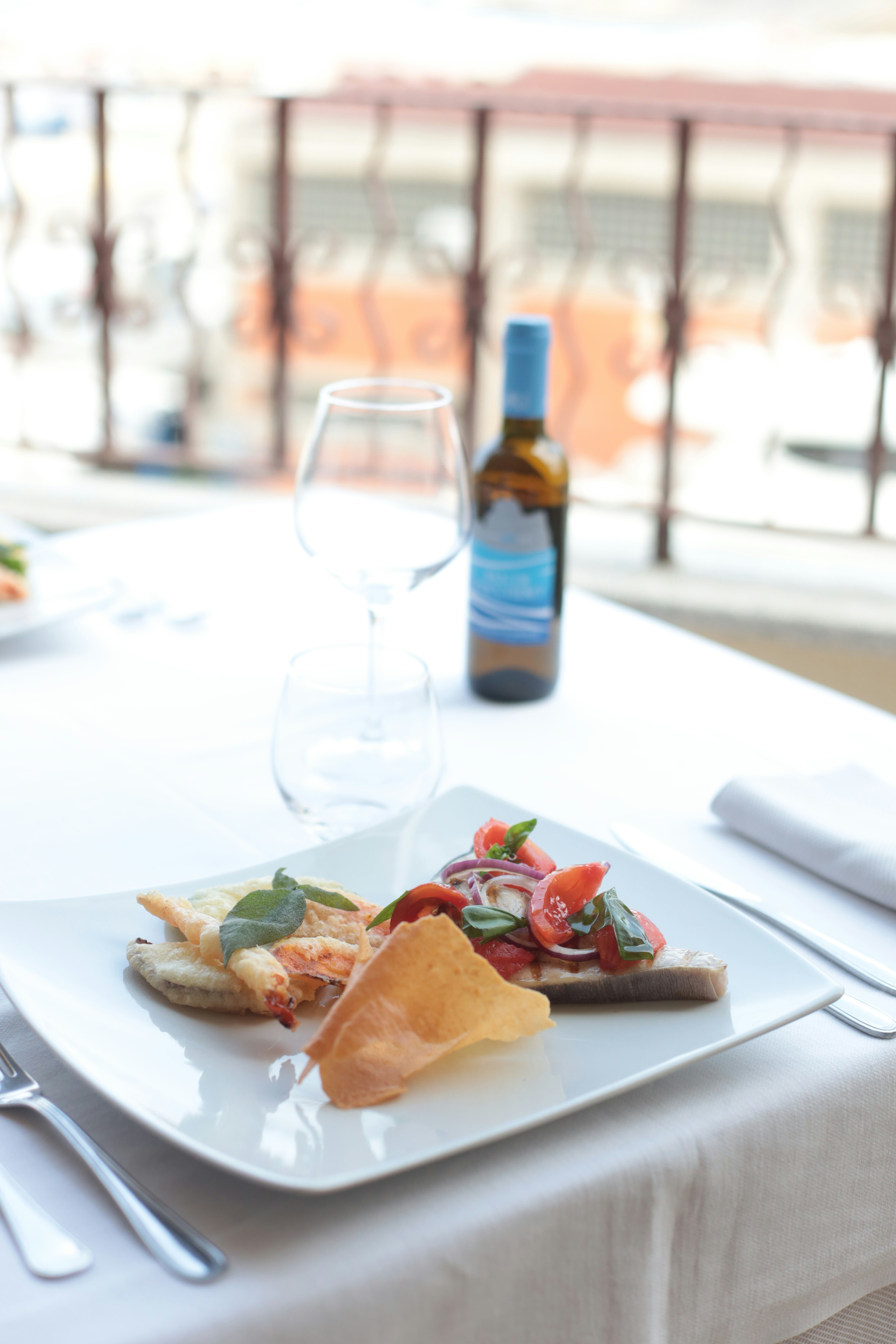 Couple of tapas on a sunlit balcony with wine and glassware