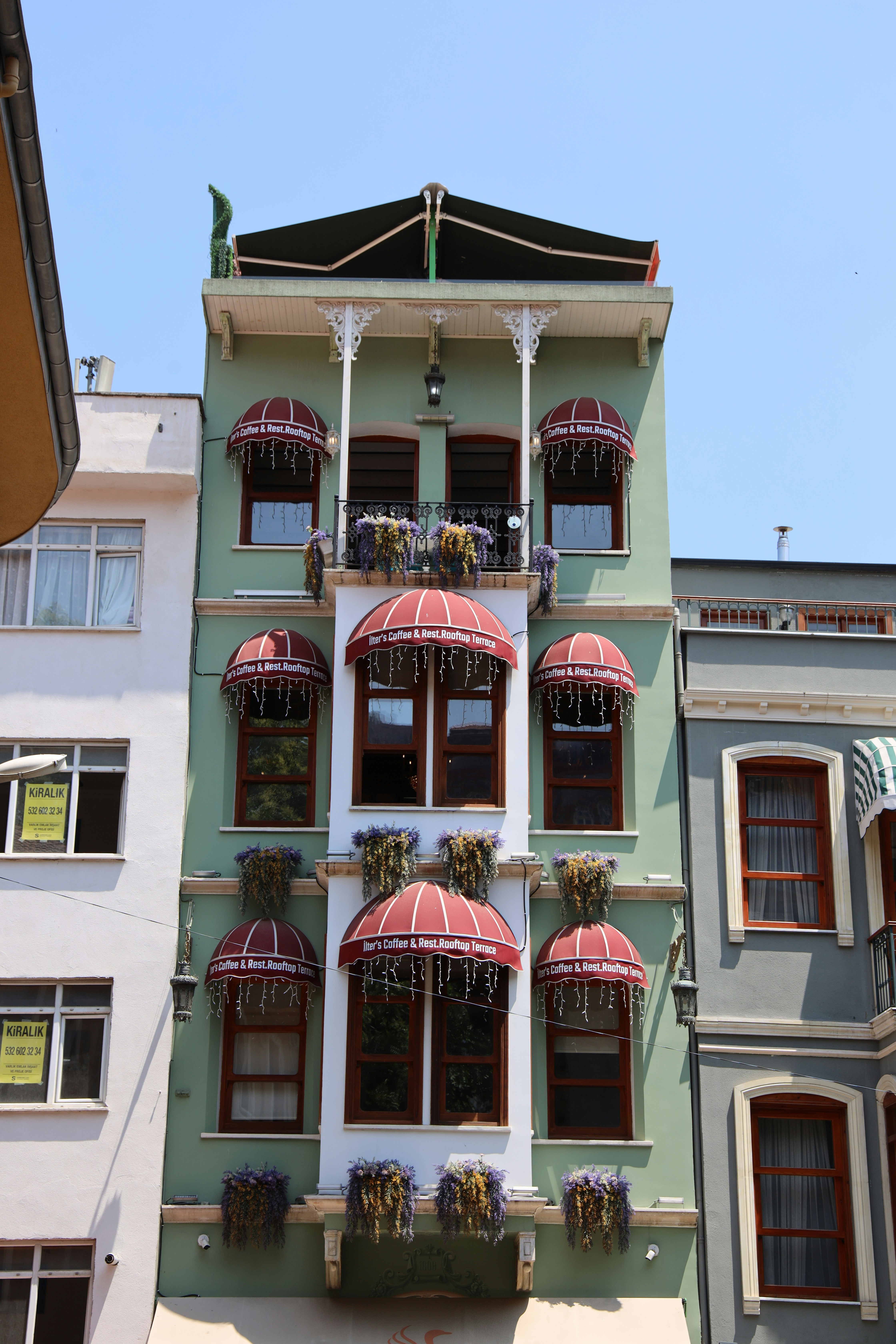 Verdant Facade with Red Canopies: A Floral Balcony Stack