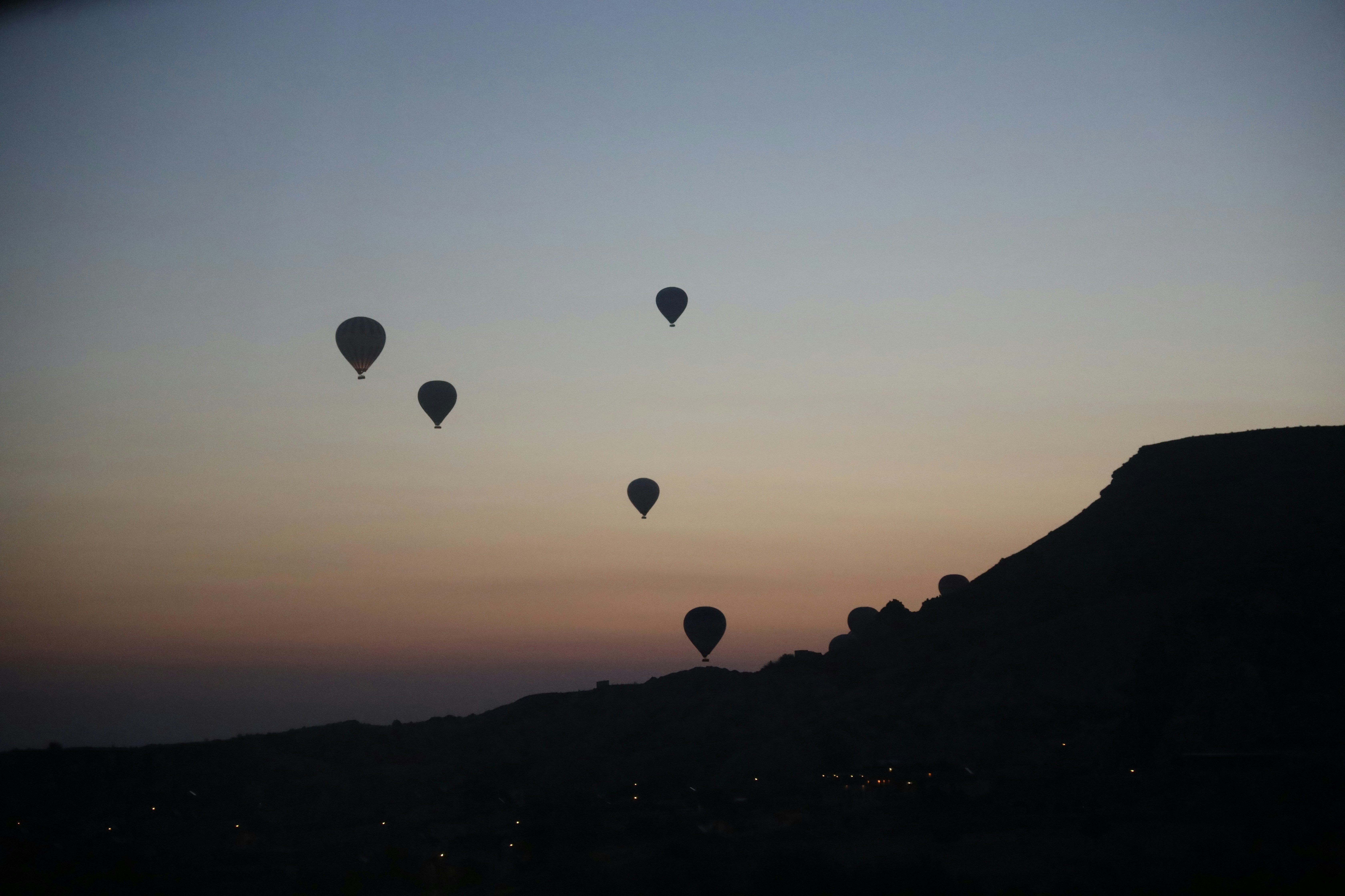 Ballooning silhouettes at dusk over a quiet ridge