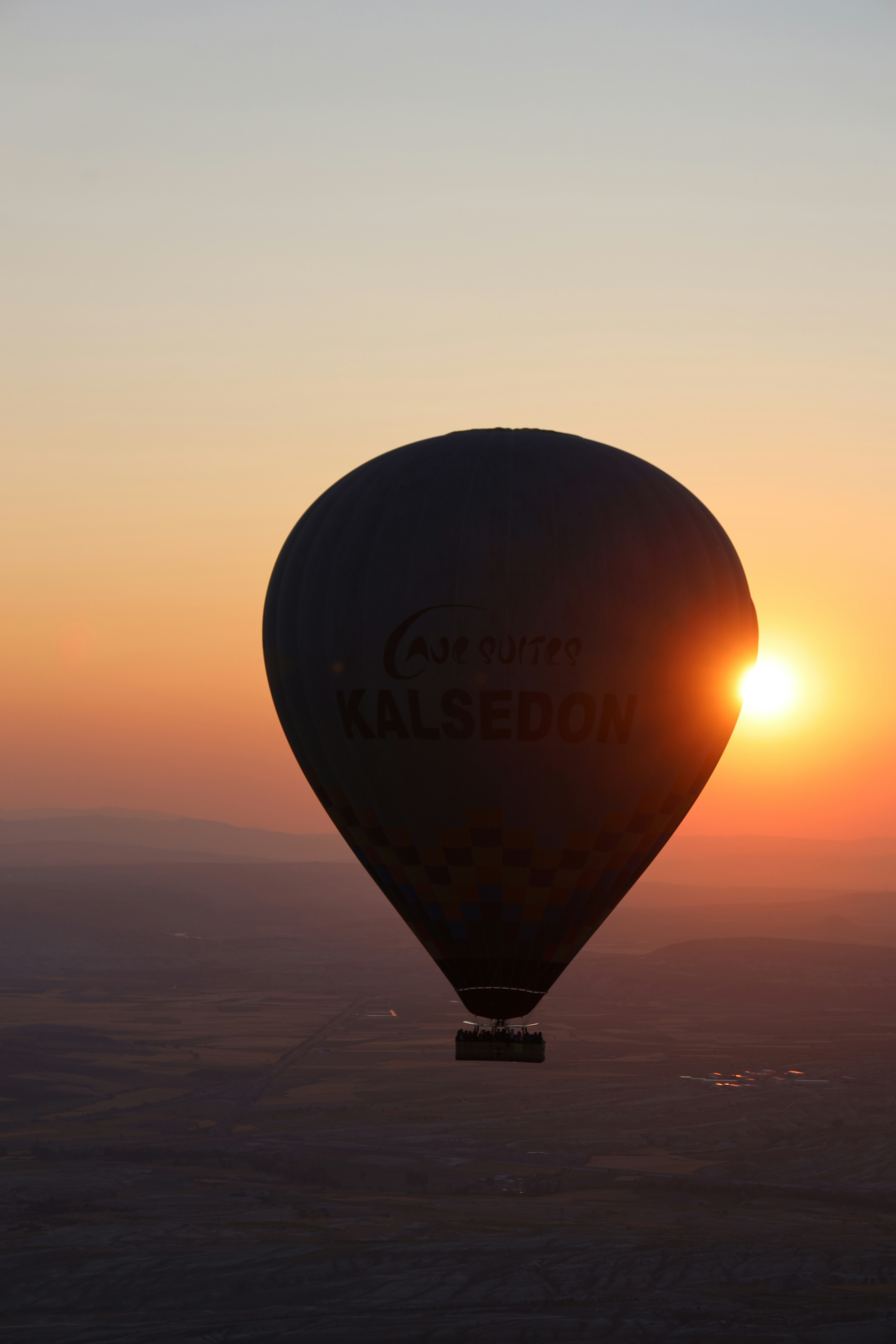 Sunlit ascent: a hot air balloon drifting above a calm horizon at dawn
