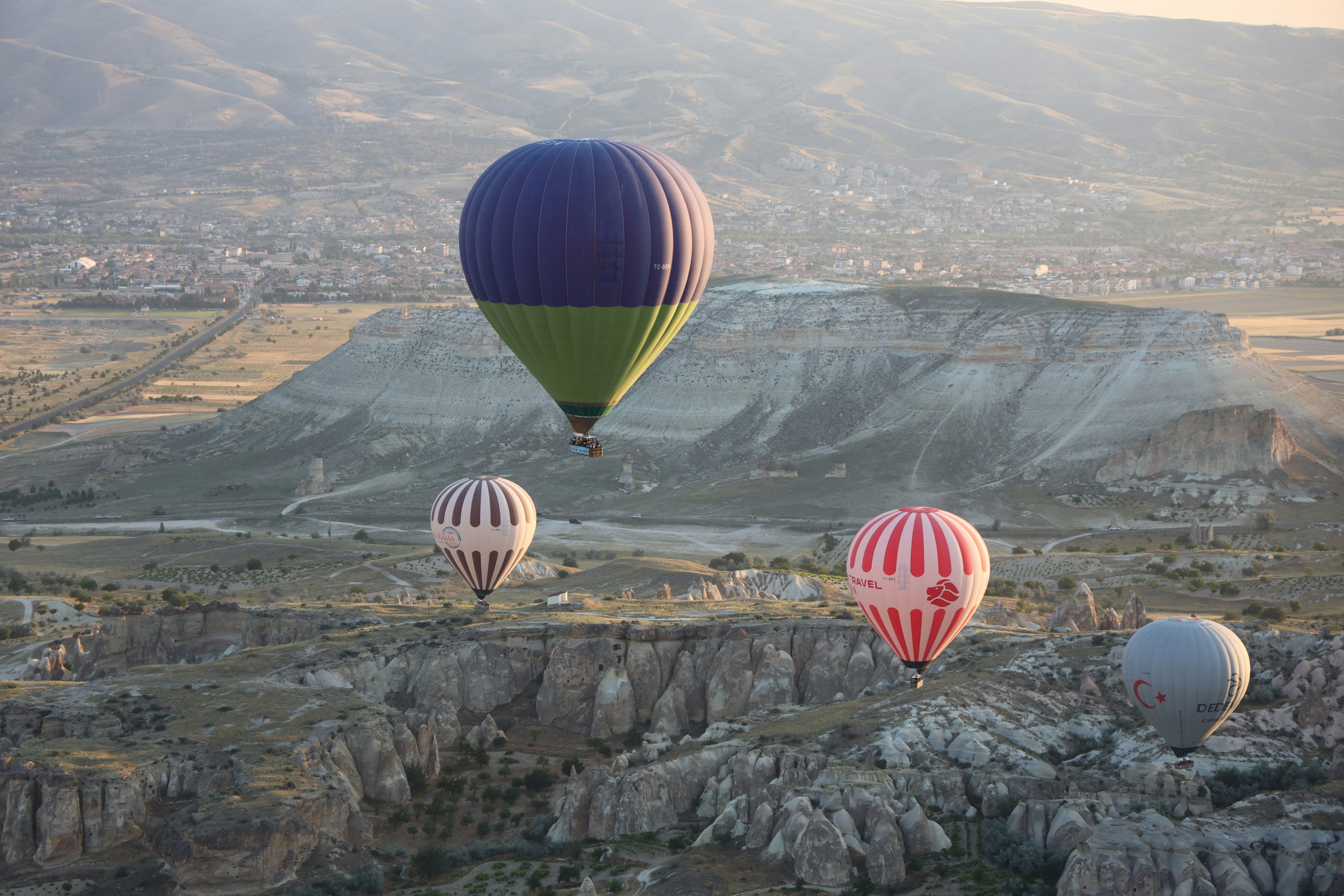 Ridgeward Balloons: A Trio of Airborne Orbs Over Eroded Cliffs