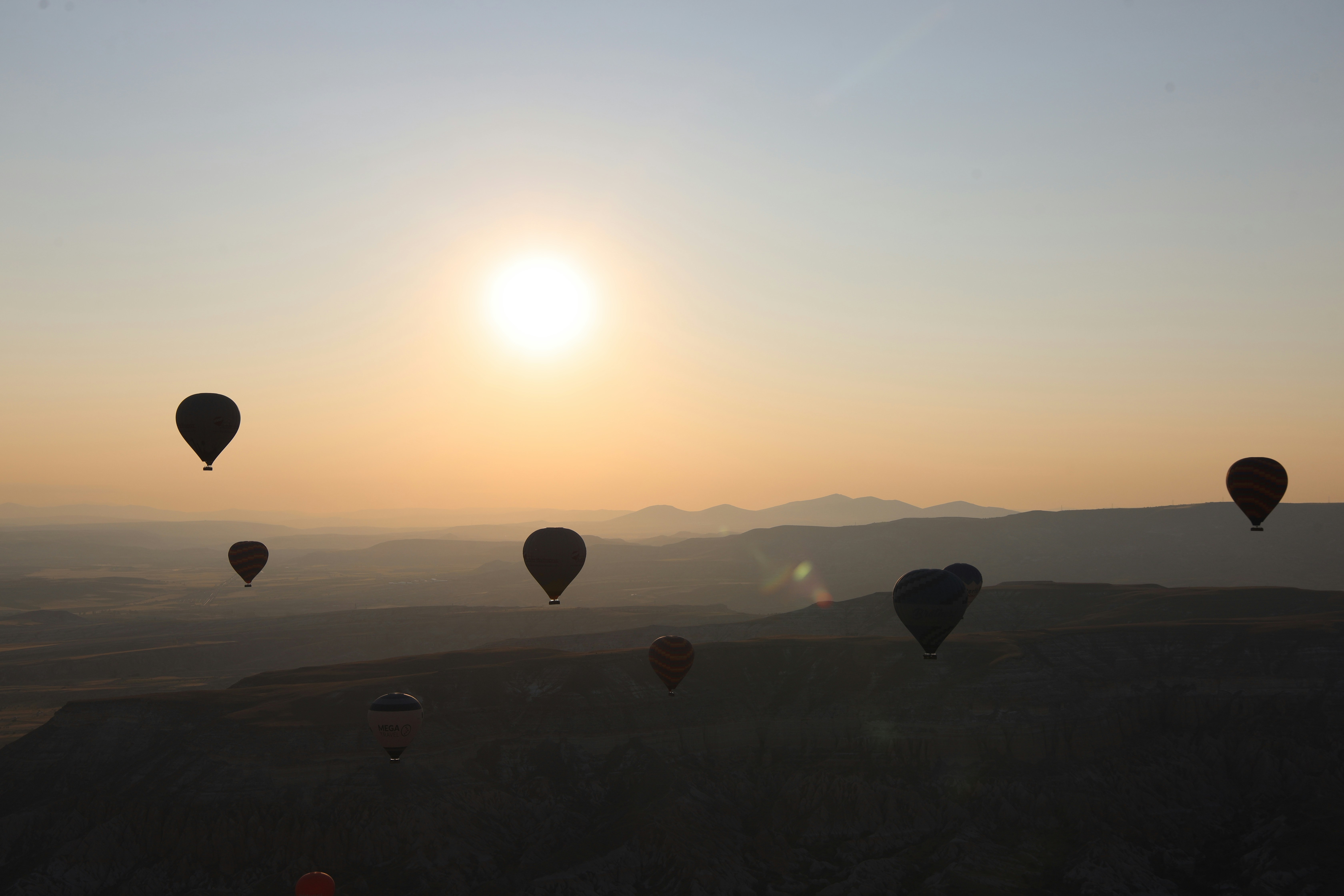 Sunrise Soaring: Balloons Drift Over Misty Valleys