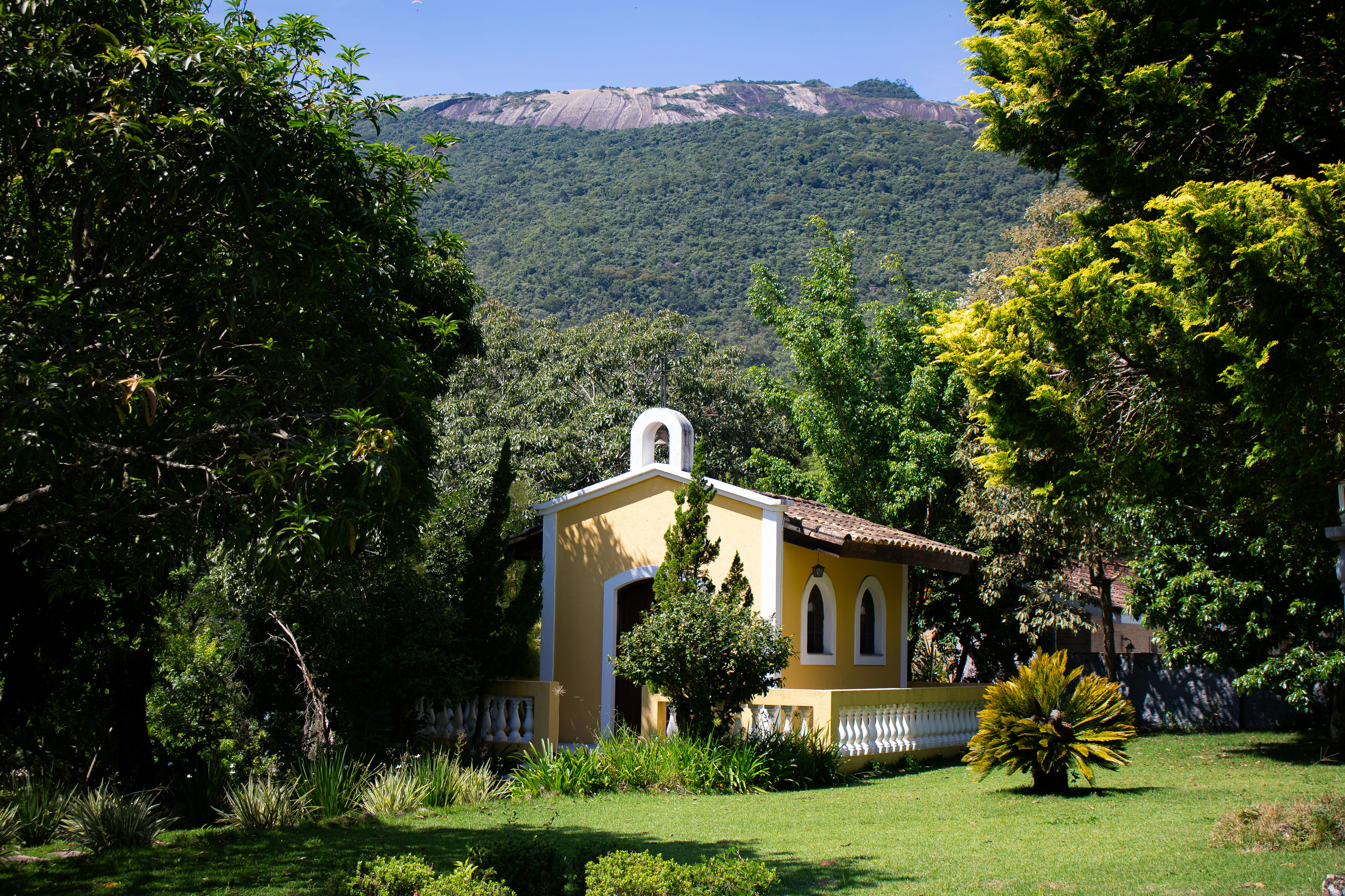Sunny Chapel Amid Greenery with Mountain Backdrop