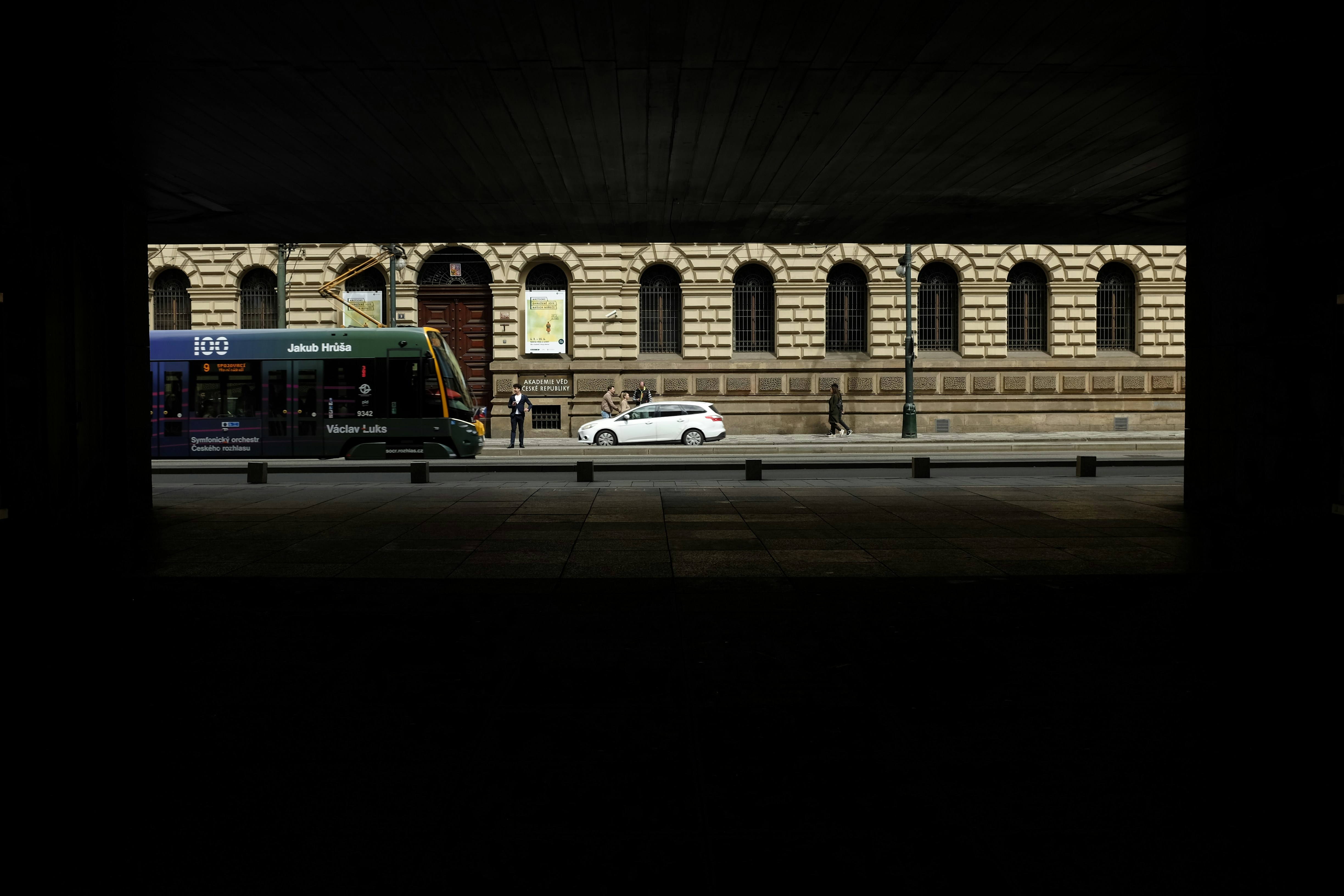 City Edge: Bus, Car, and Heritage Facade Framed by a Dark Tunnel