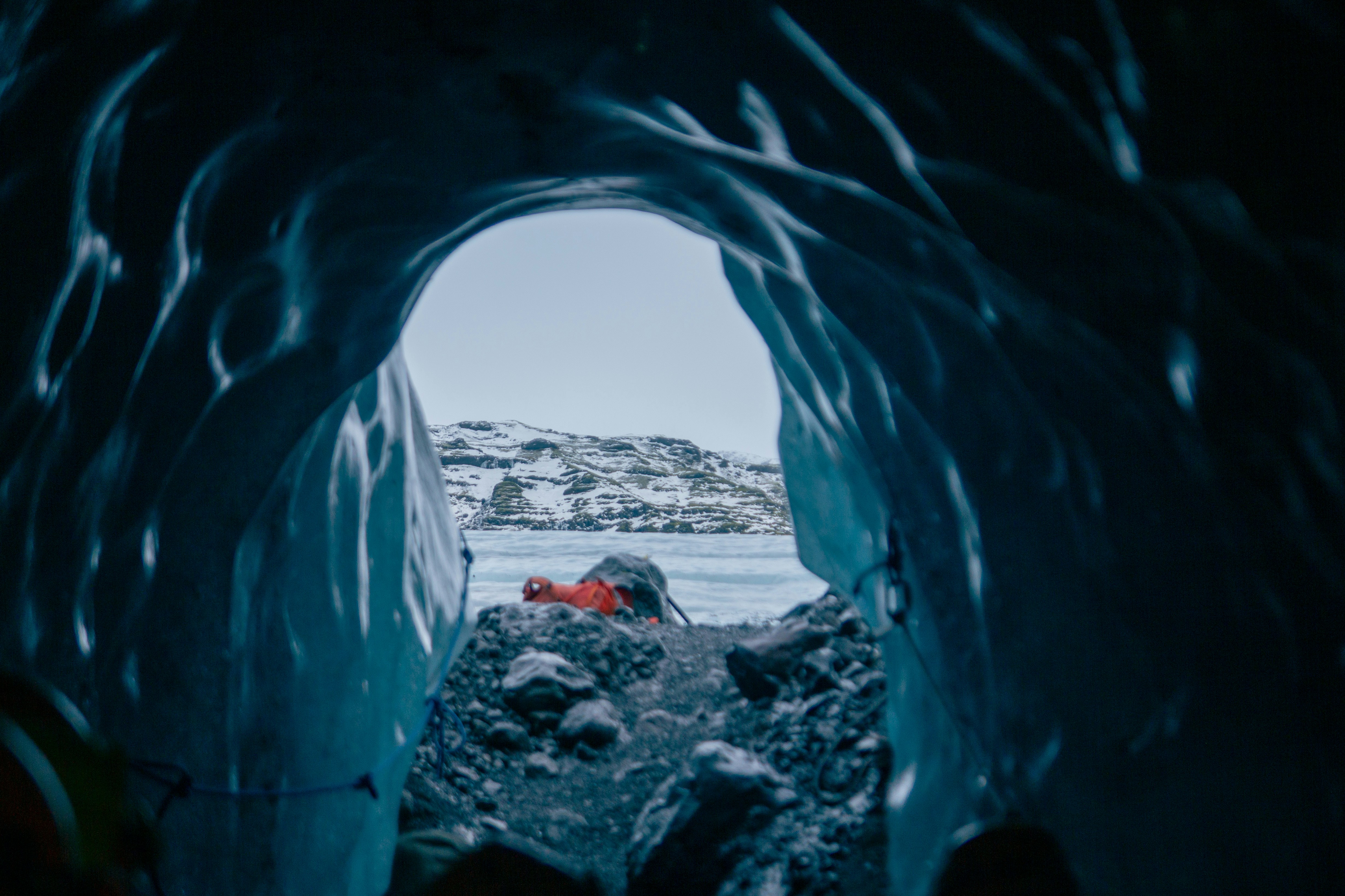 Ice-blue tunnel to the distant shore: a camp scene framed by melt-lit ice