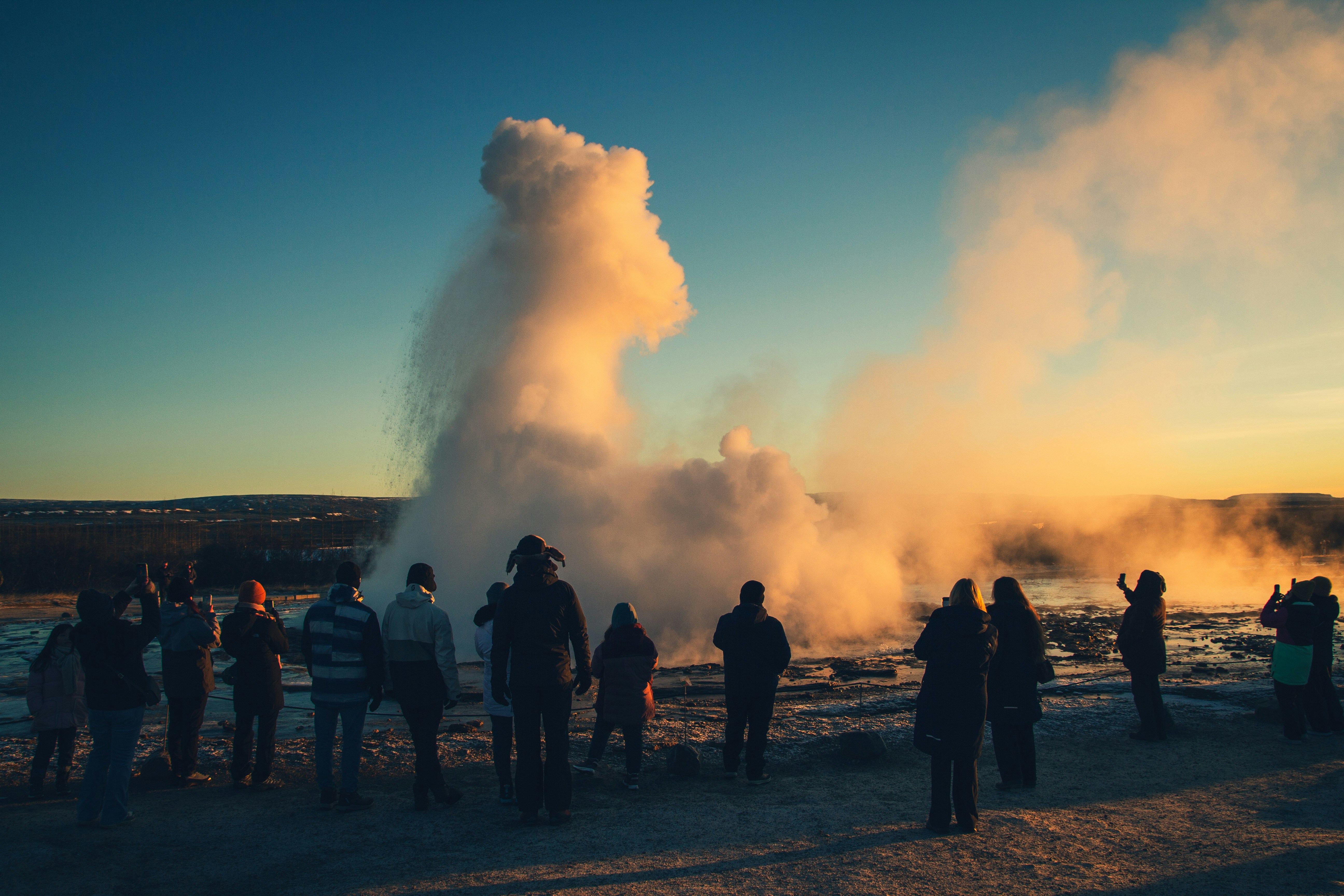 Steam Burst at Sunset: A Line of Onlookers Witness a Geyser Moment