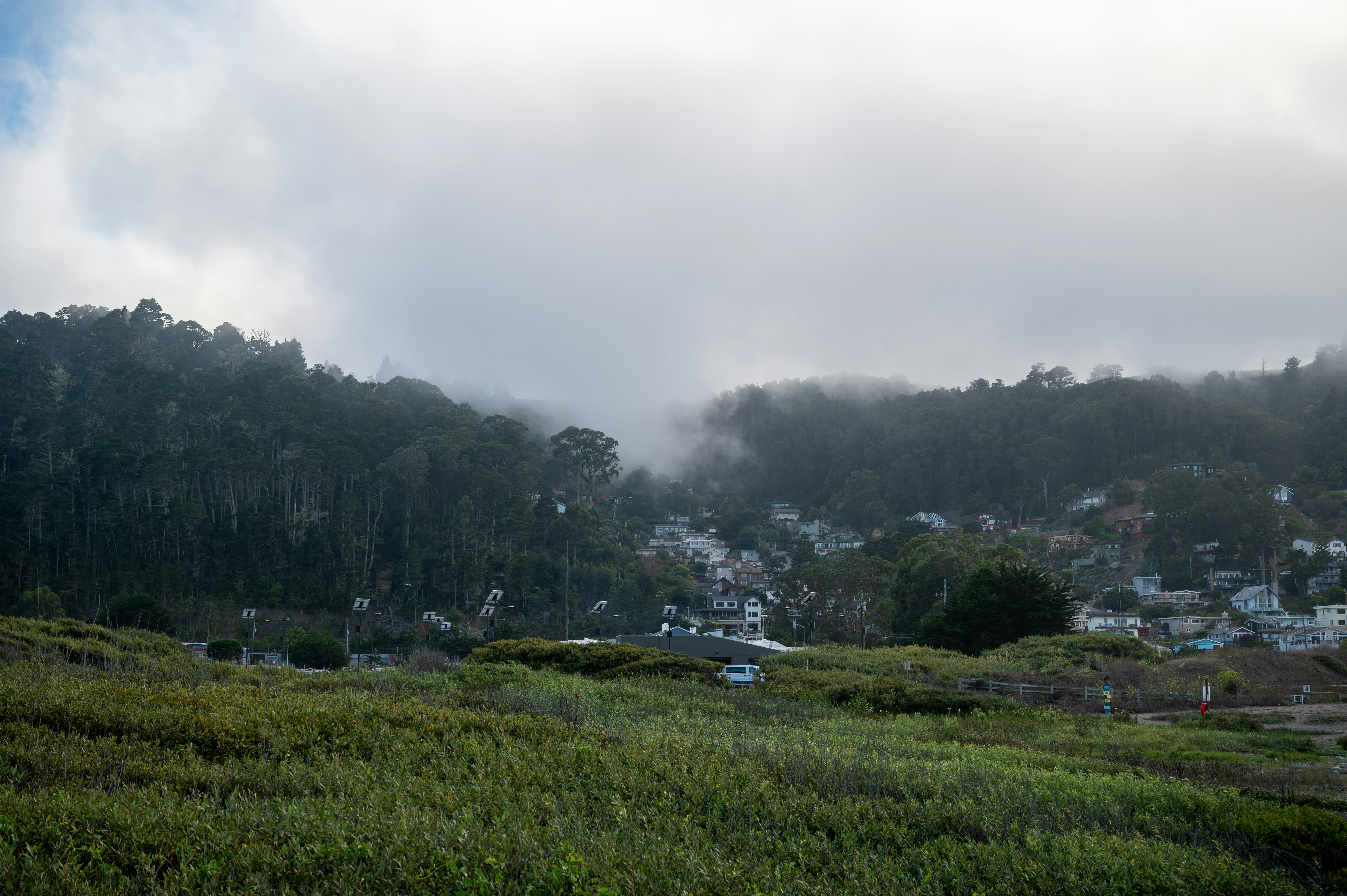 Pacifica hillside homes partly covered by low coastal fog.