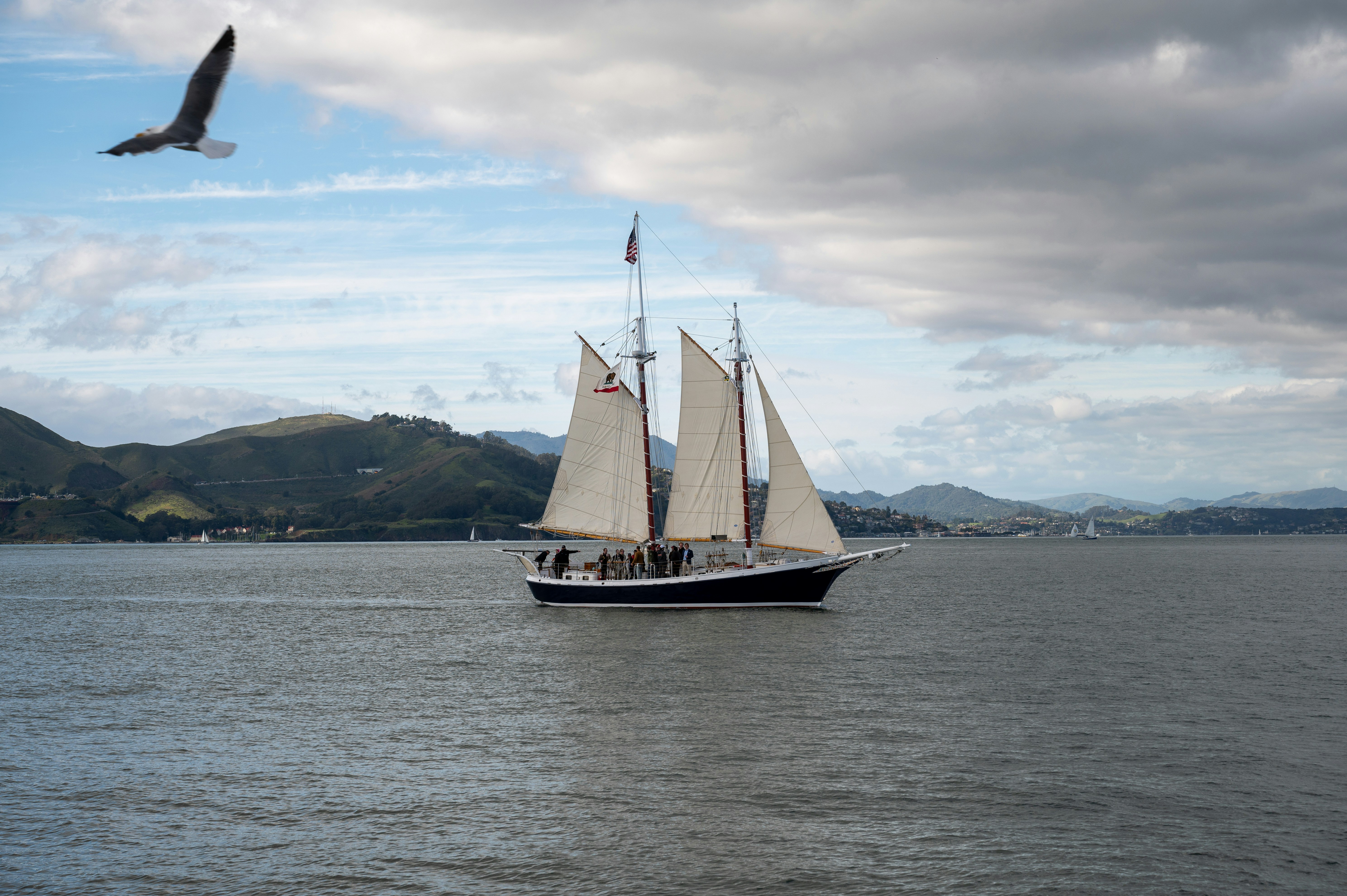 Sailboat on calm harbor under sweeping clouds