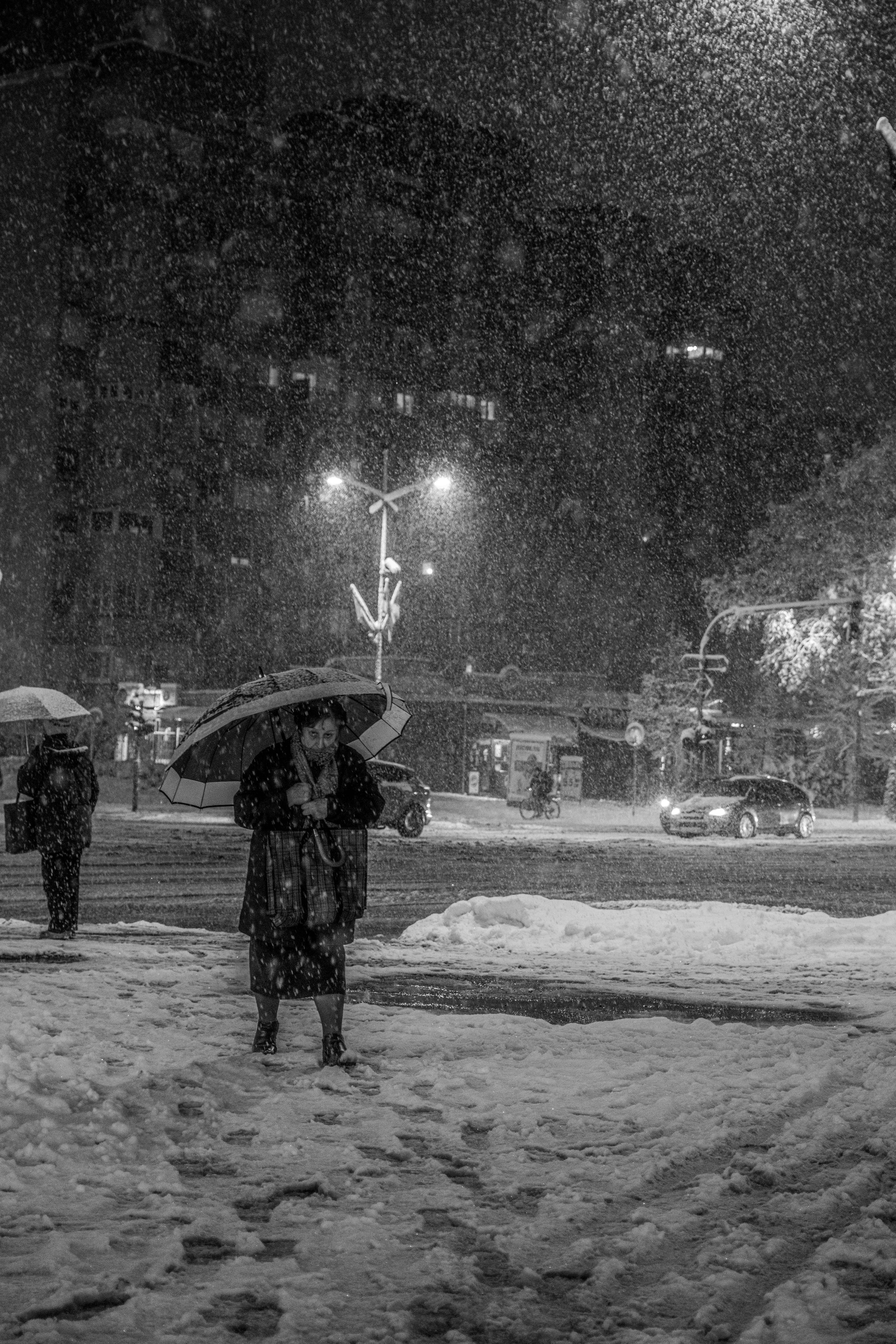Snowy Night Crossroad: Umbrella Figure in Stilled Streetlit Snow