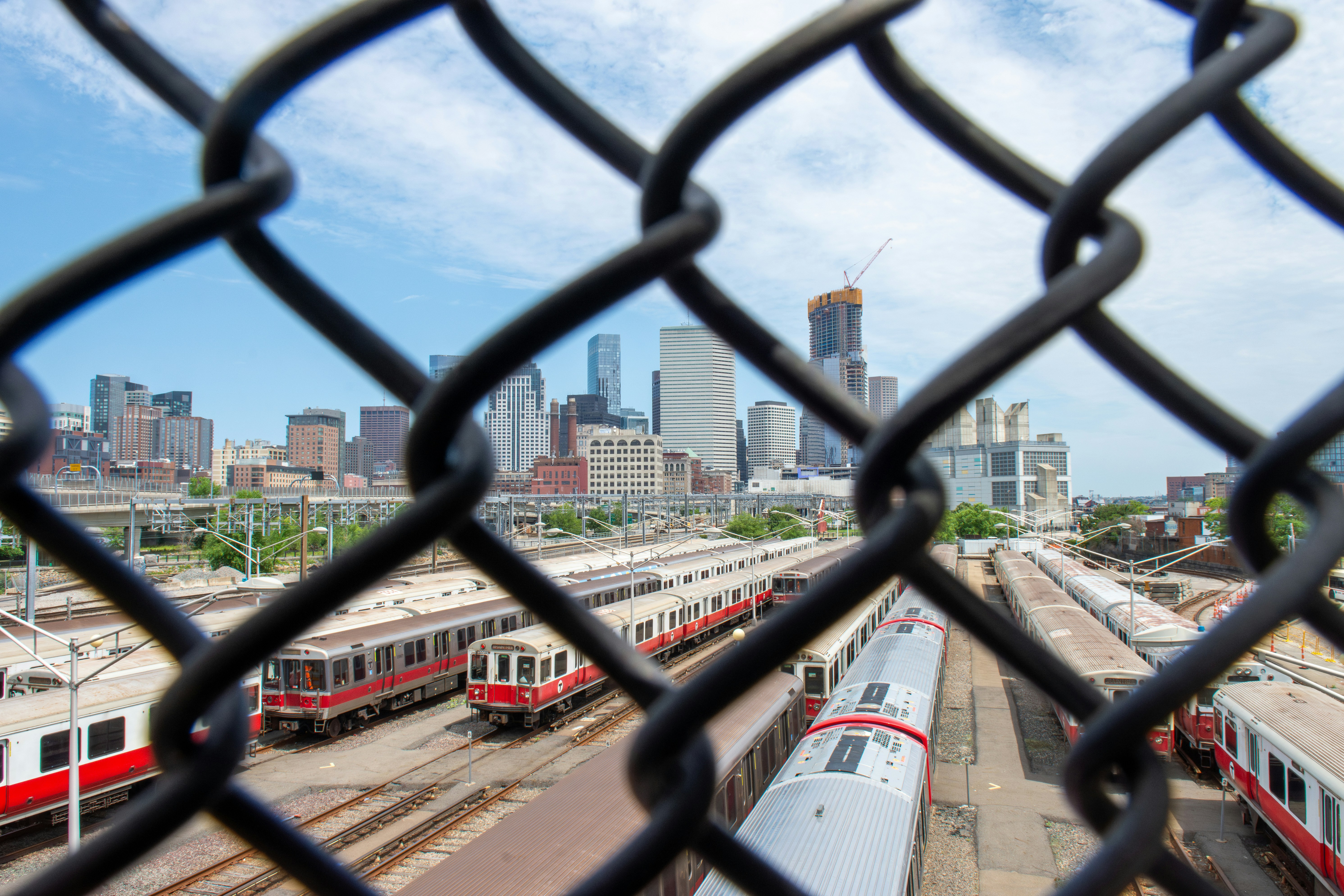 Cityscape Framed by Chains: Train Yards Behind a Fence
