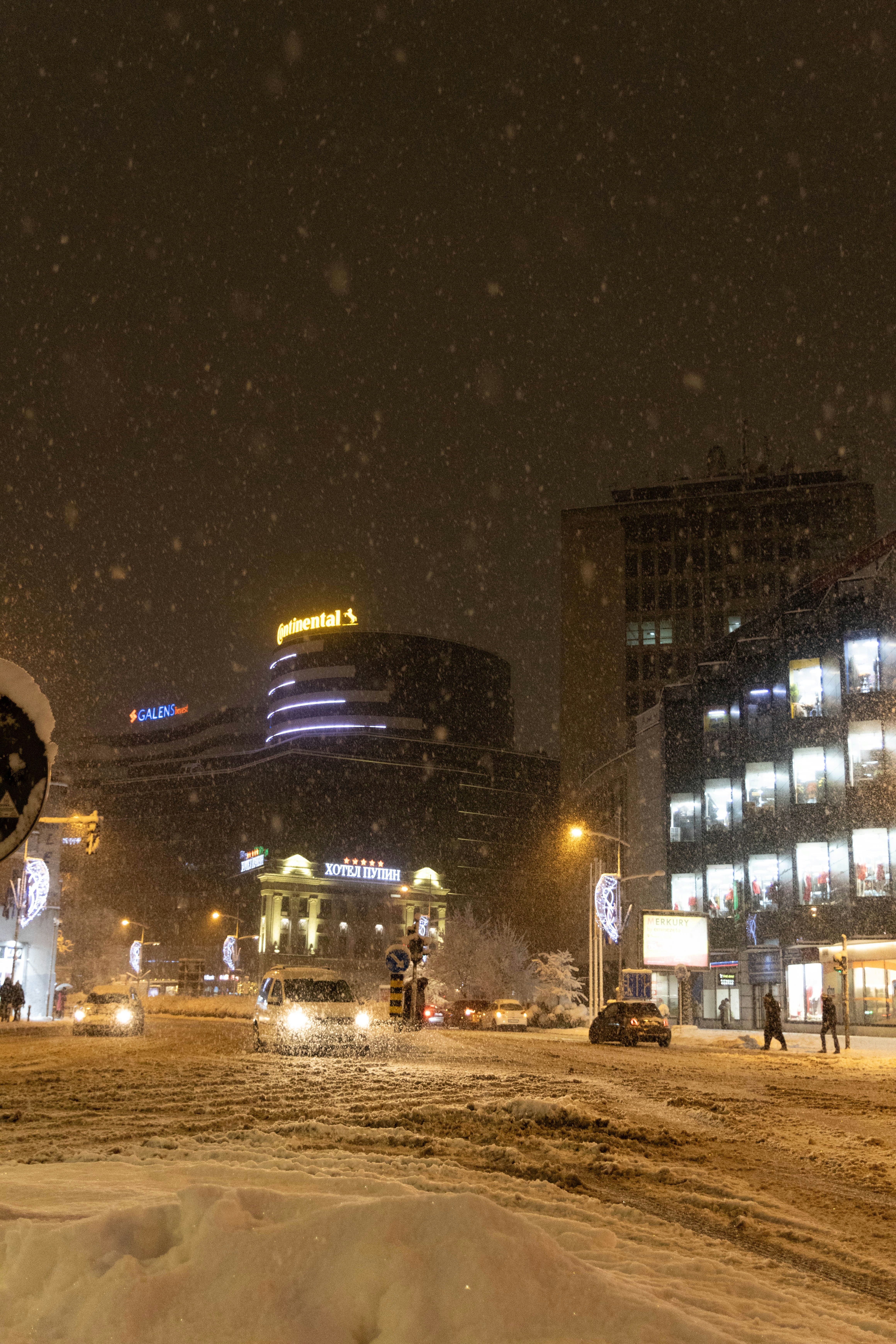 Snowfall over a lit city square