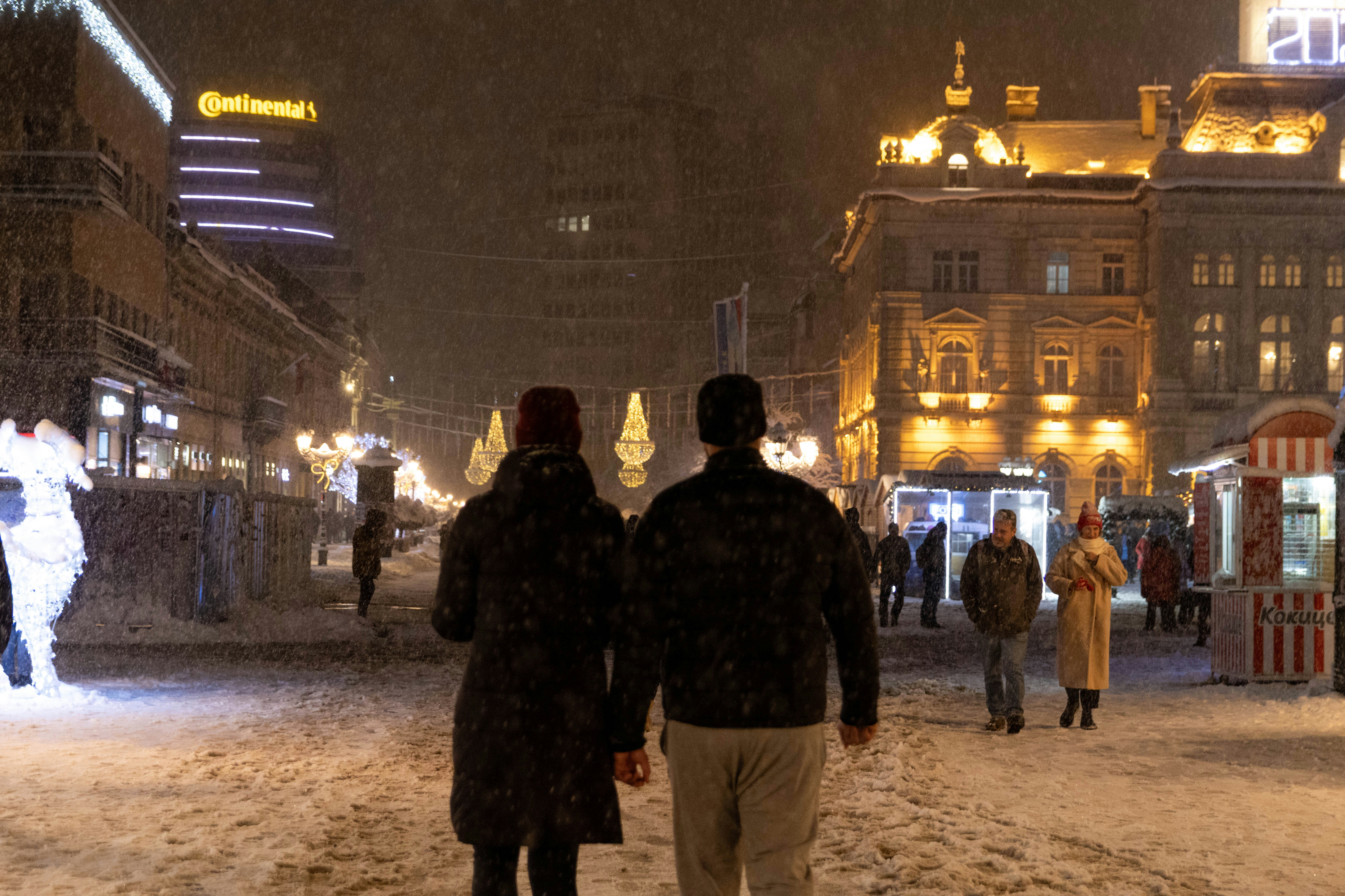 Winter Afterglow: Two silhouettes in a Mid-City Snowfall