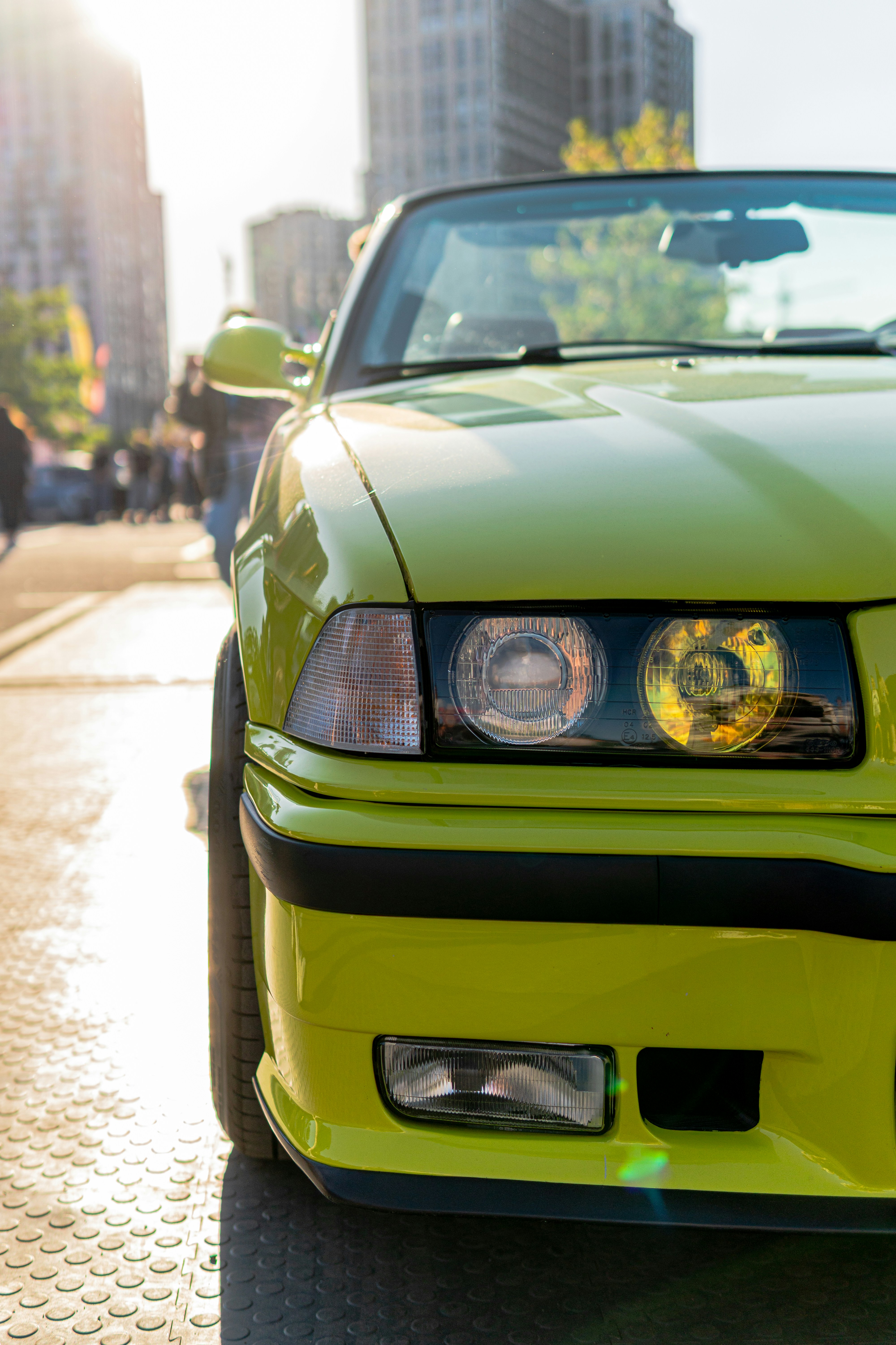 Vibrant yellow car parked on a sunny city street.
