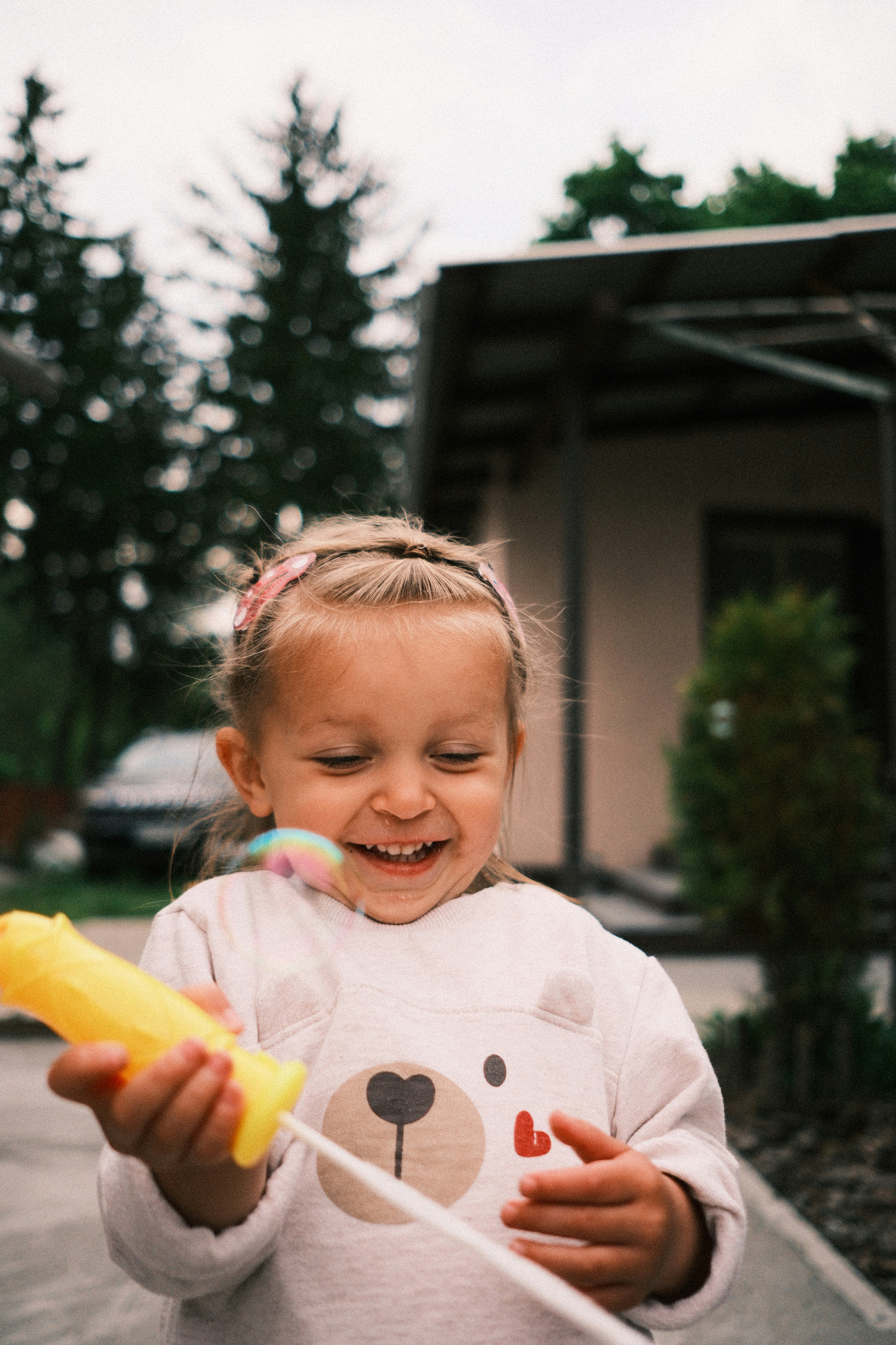 Joyful bubble moment: a toddler's grin with a yellow toy and rainbow soap bubble