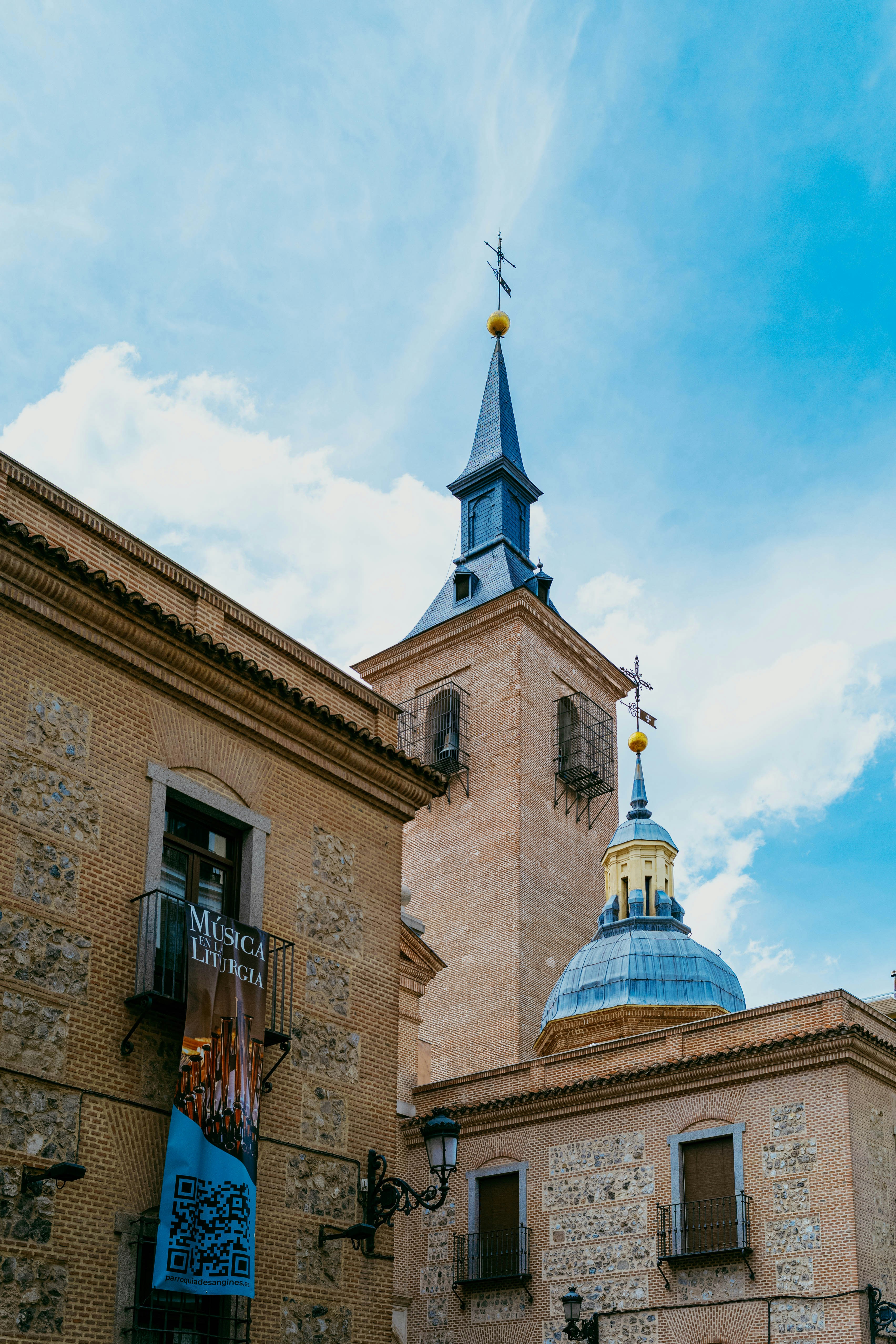 Historic Spanish plaza with church spire and blue dome under a bright sky