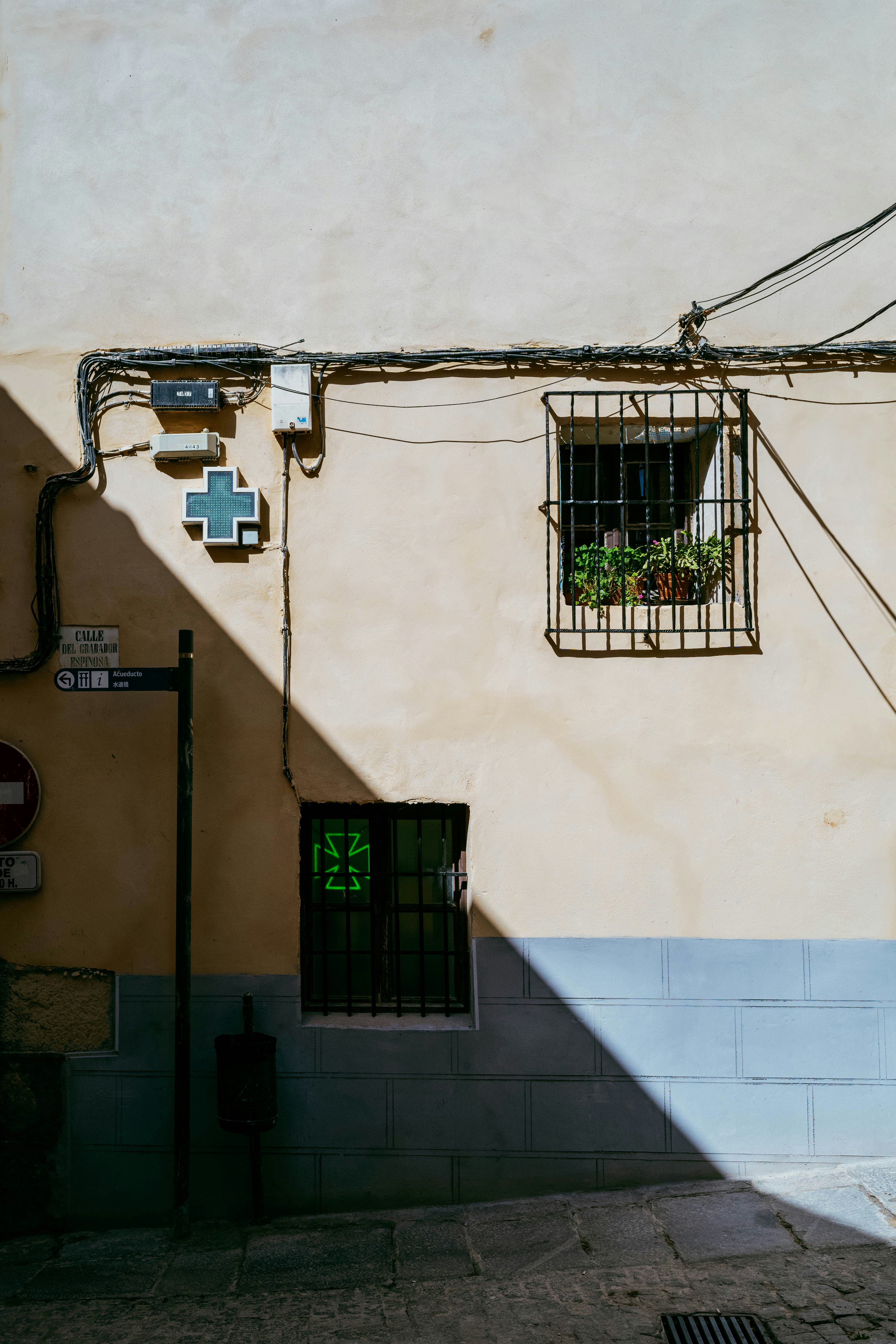 Sunlit Facade: Shadowed Archways and a Neon Green Cross