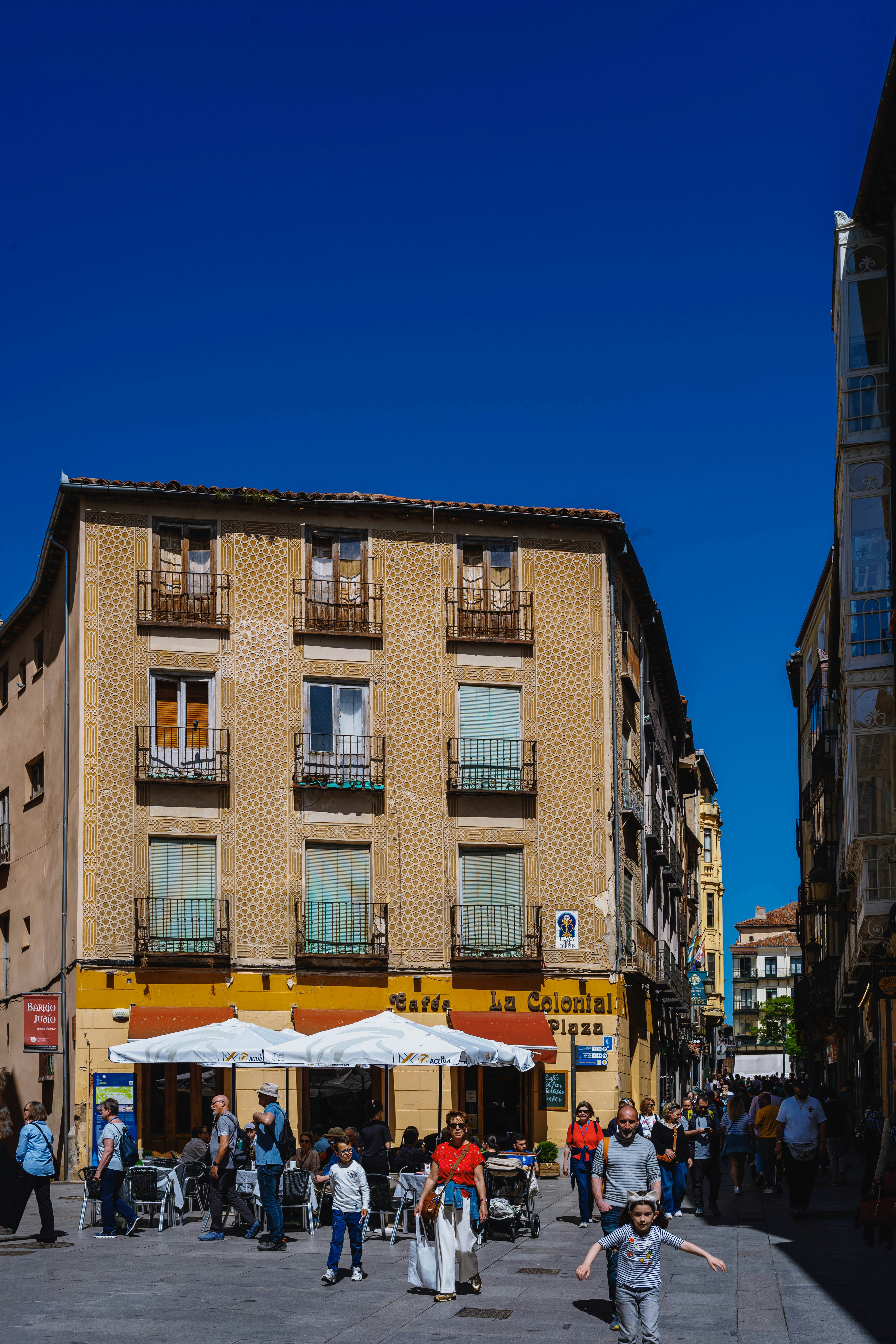 Cobbled Corner: Sunlit Plaza Beneath a Facade of Tiles