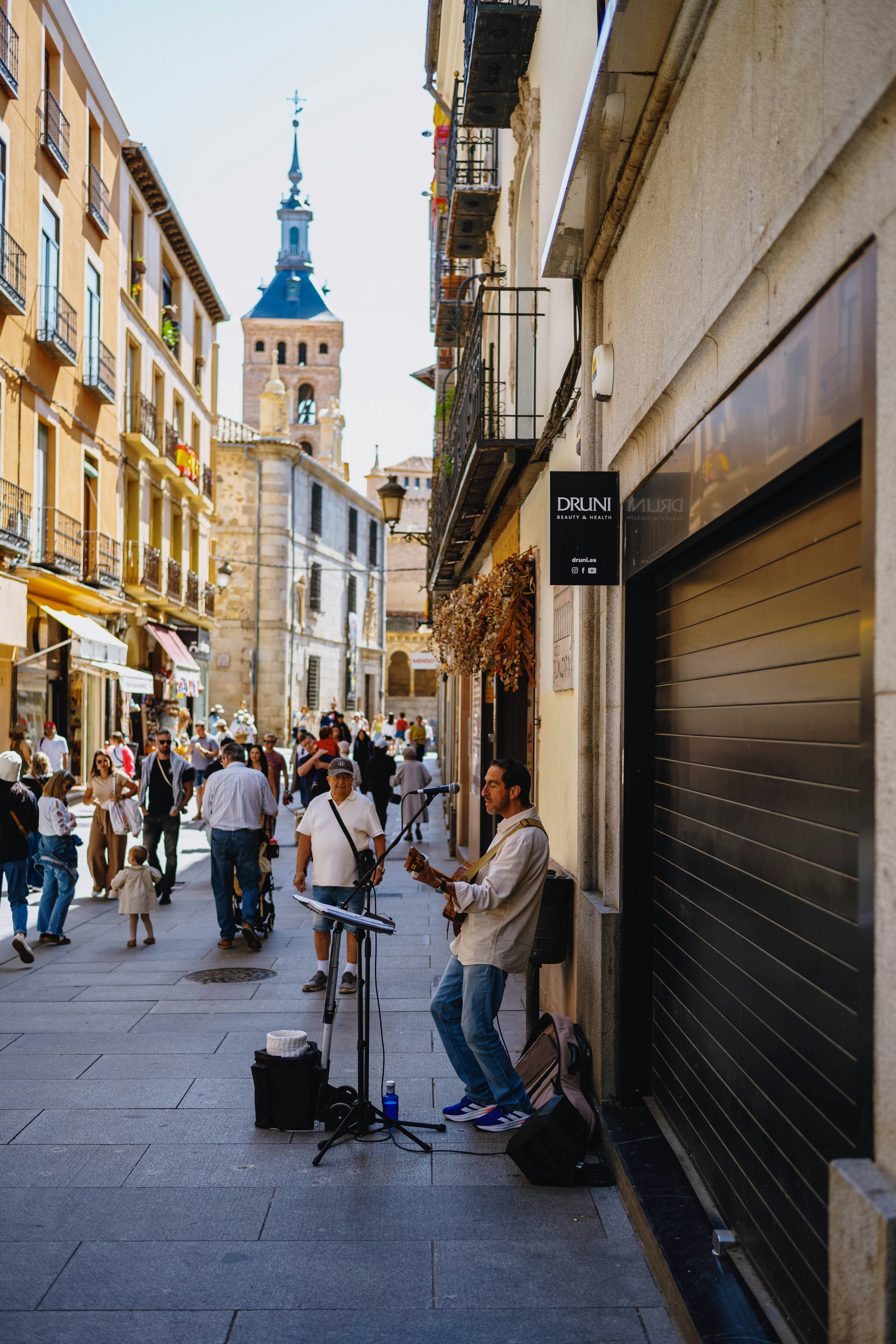 Guitarist in a Sunlit Calle with Clocktower Backdrop