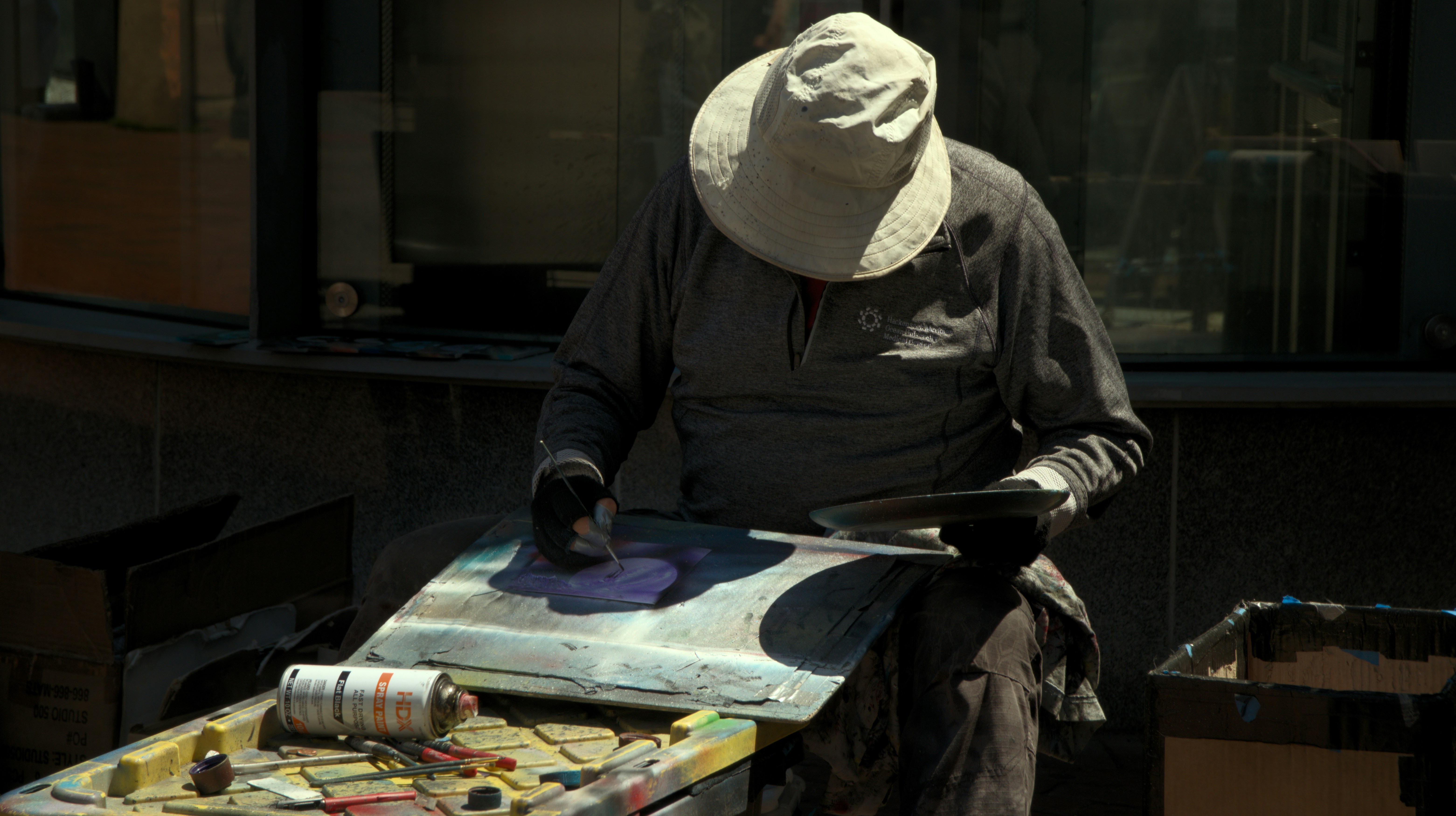 Hushed Focus: A Street Artist in Shadowed Light