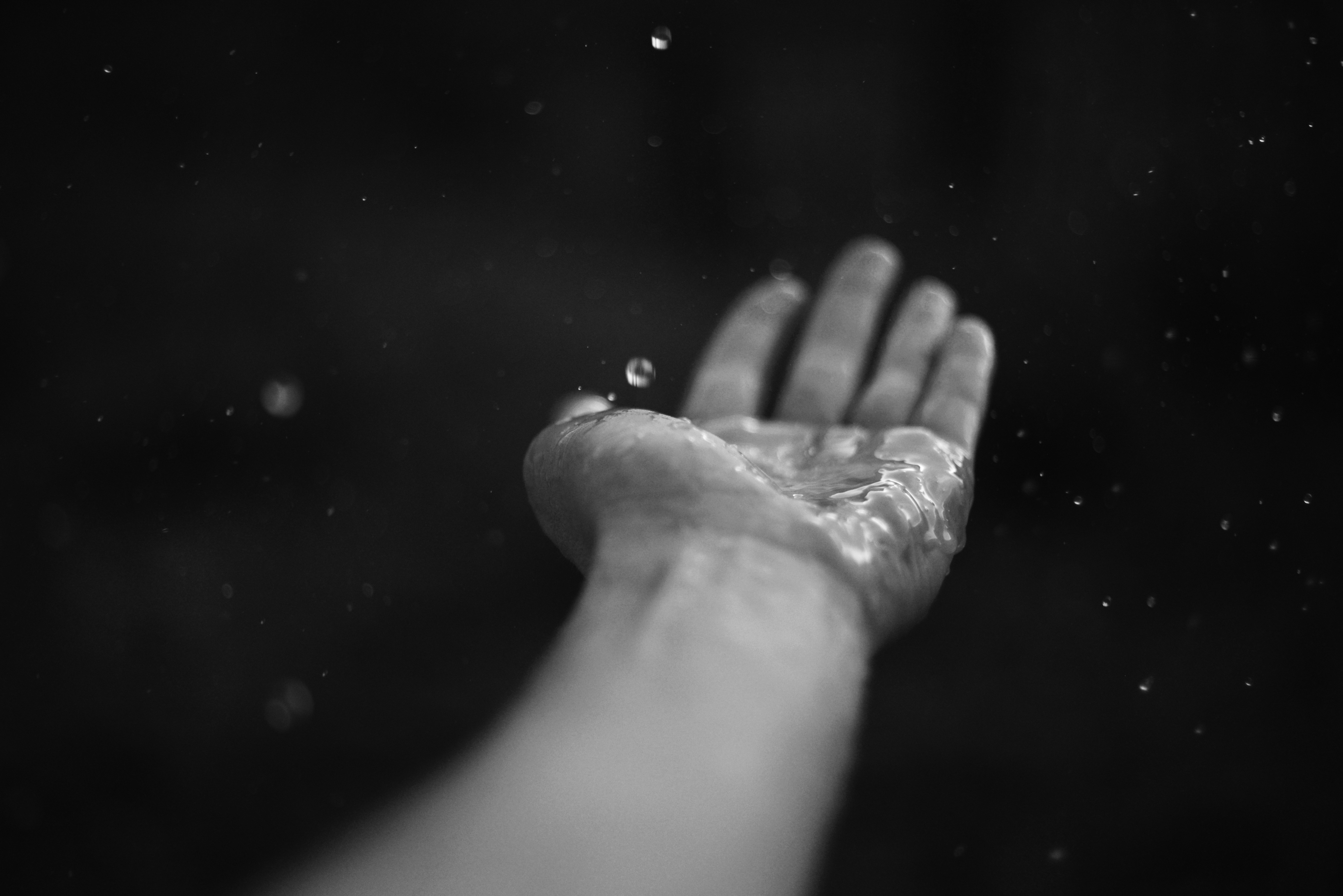 In the Deluge: An Outstretched Hand Reaches Through Falling Raindrops