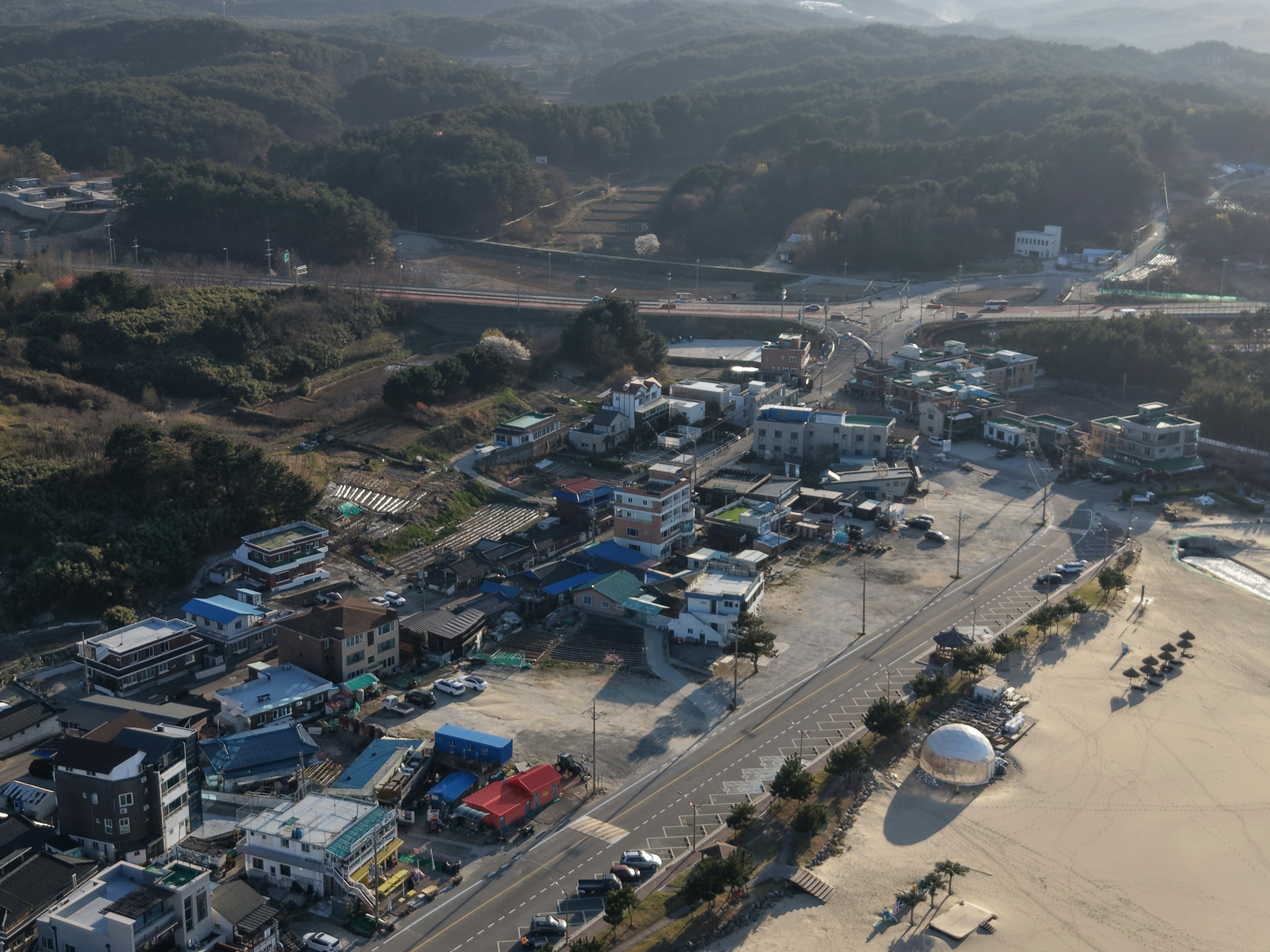 Coastal Village Aerial: Grid of Homes Meet a Crown of Dunes