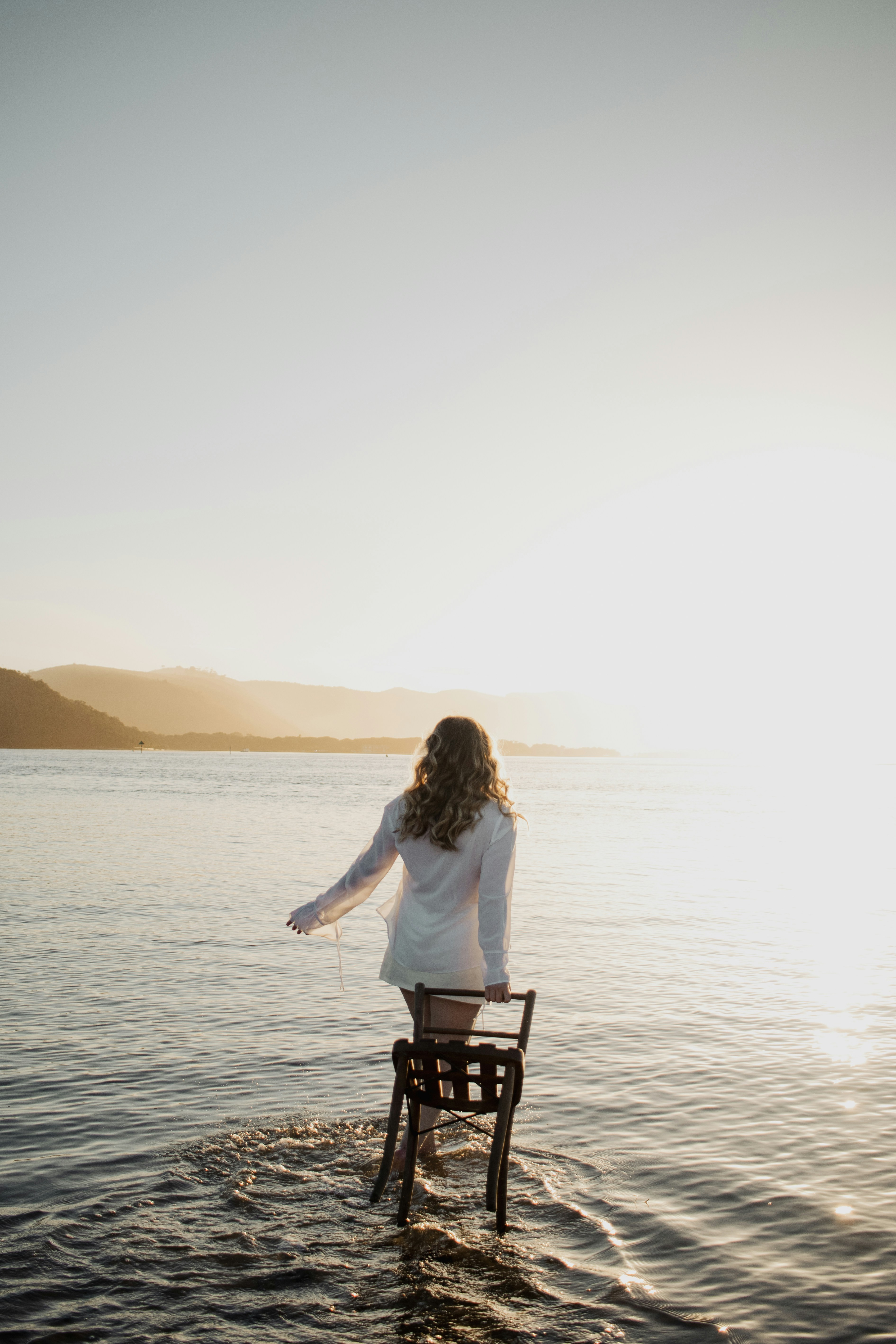 Stillness at Sunset: A Woman On a Waterfront Bench Surrounded by Gentle Waves