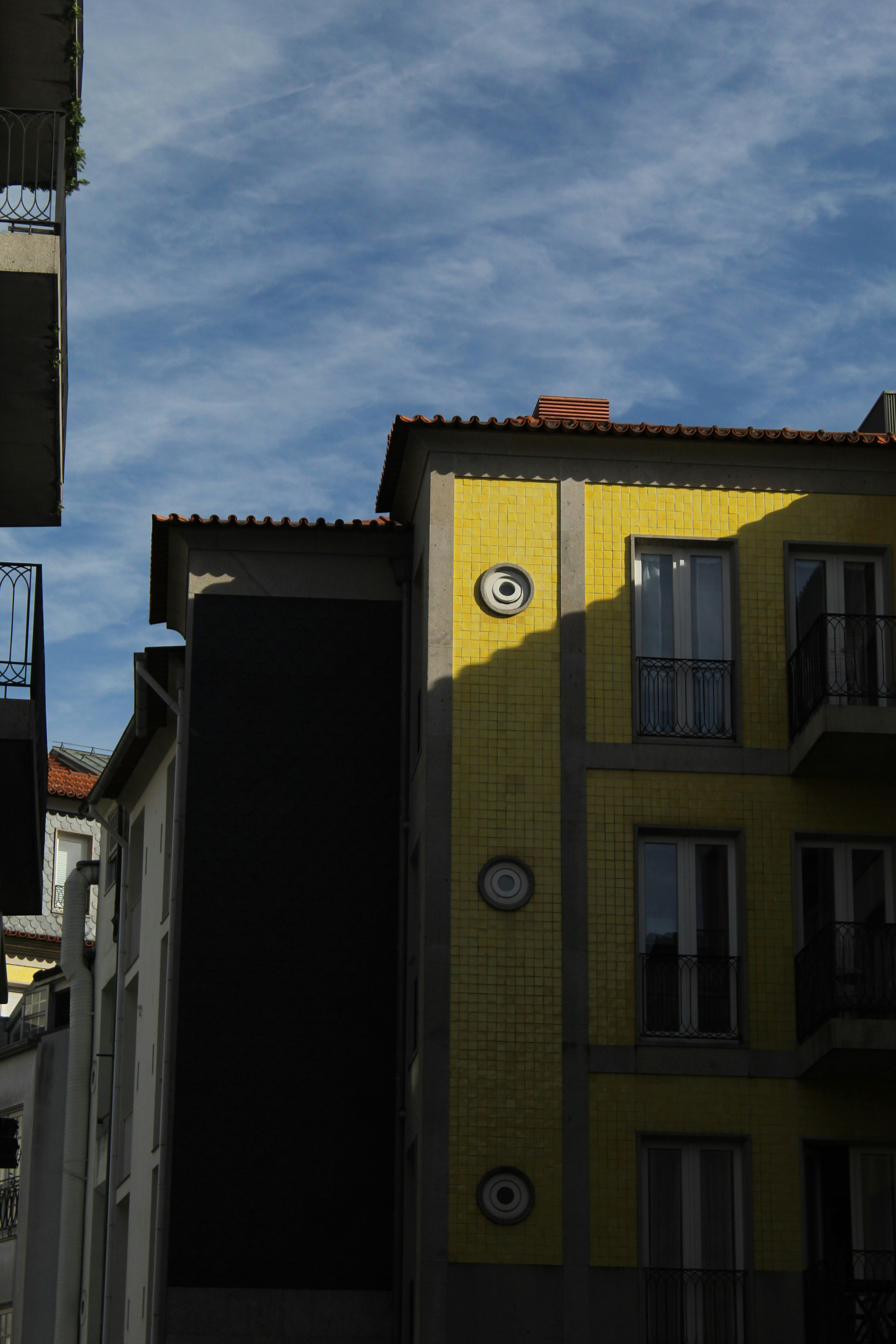 Sunlit Yellow Facade: Geometry and Shadow on a Residential Corner