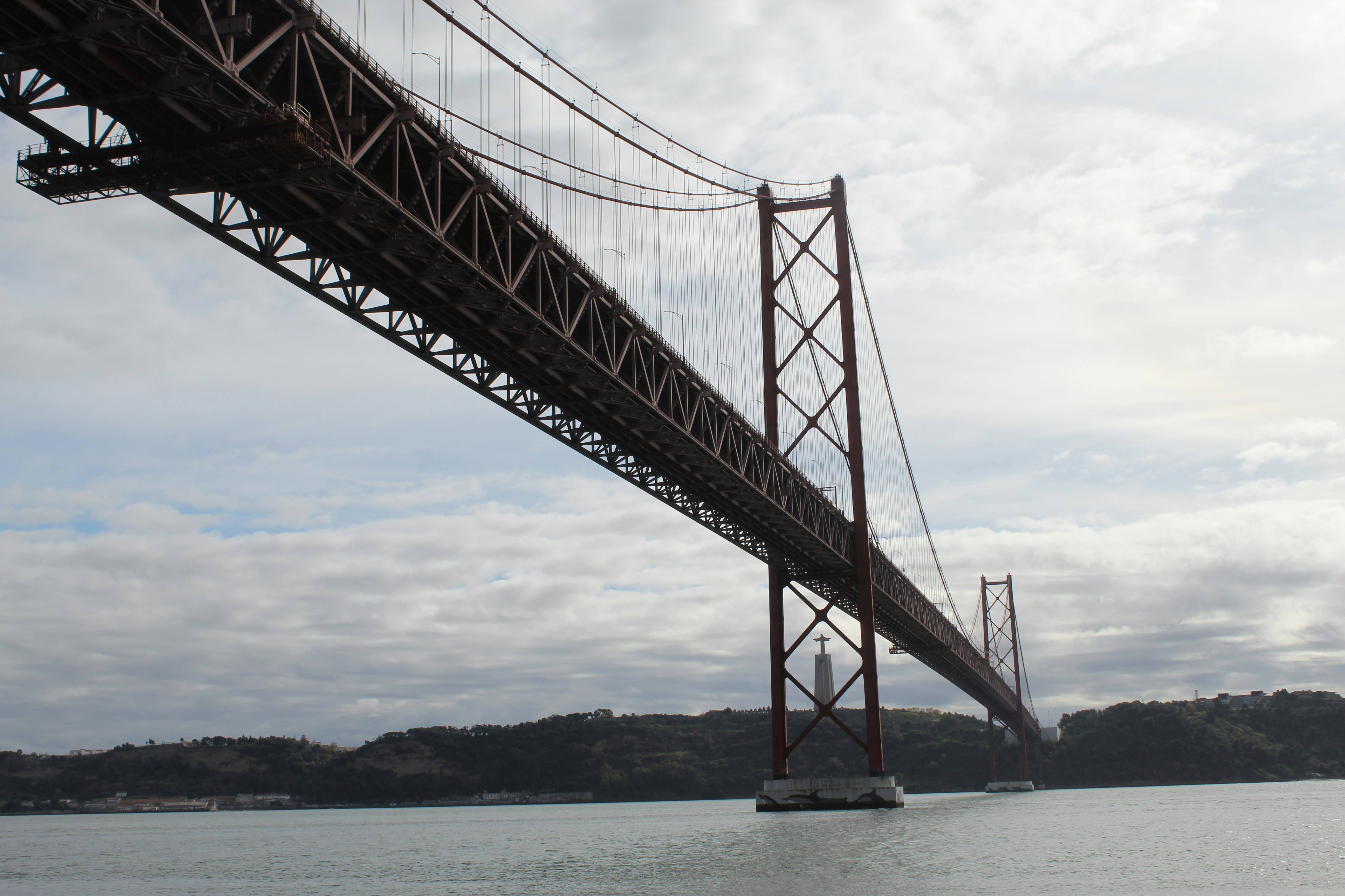 Towering Span: A Quiet Aquatic Perspective of a Red Suspension Bridge