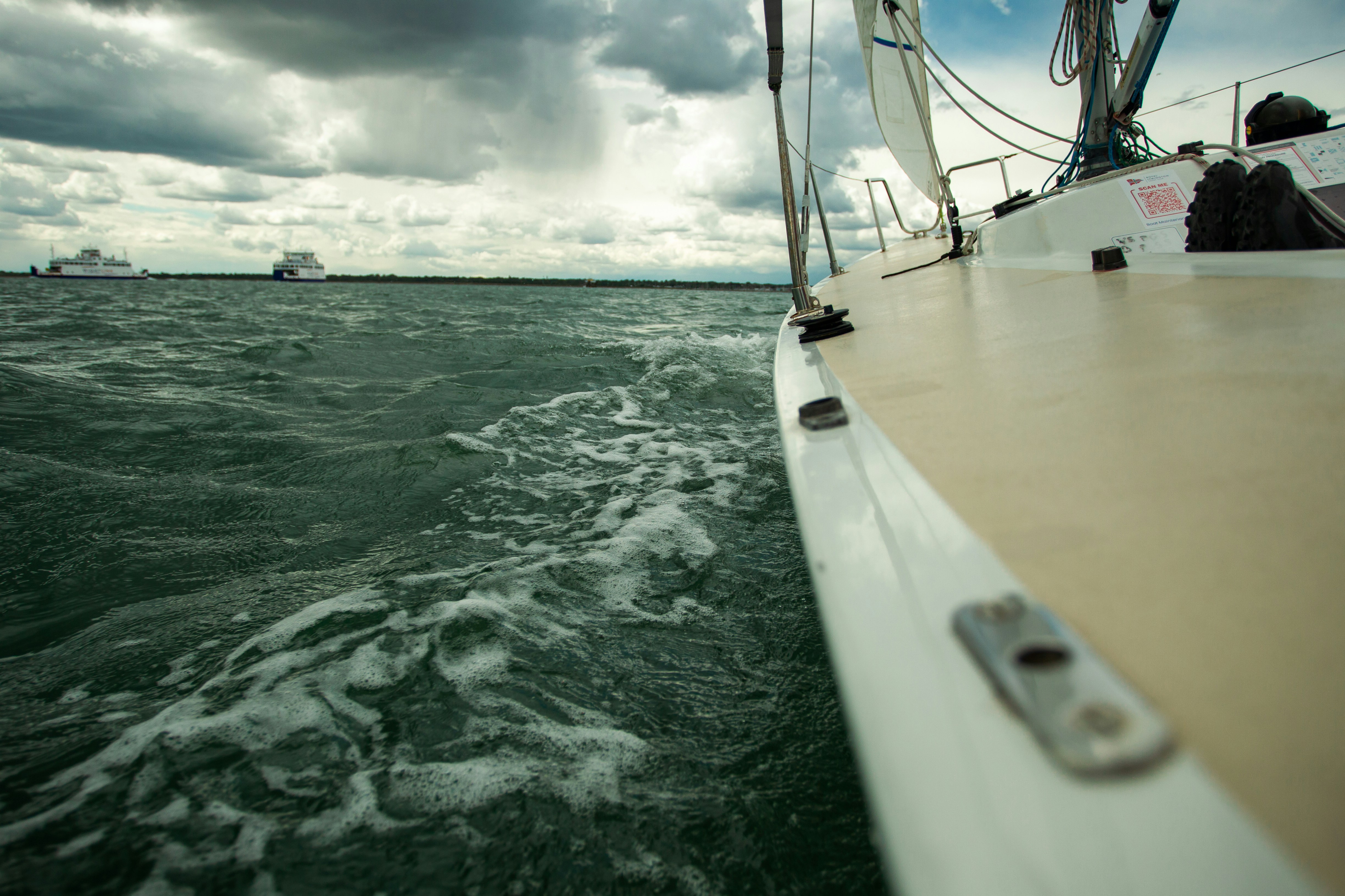 Bow against the swell: a sailboat slides along the wake at dawn