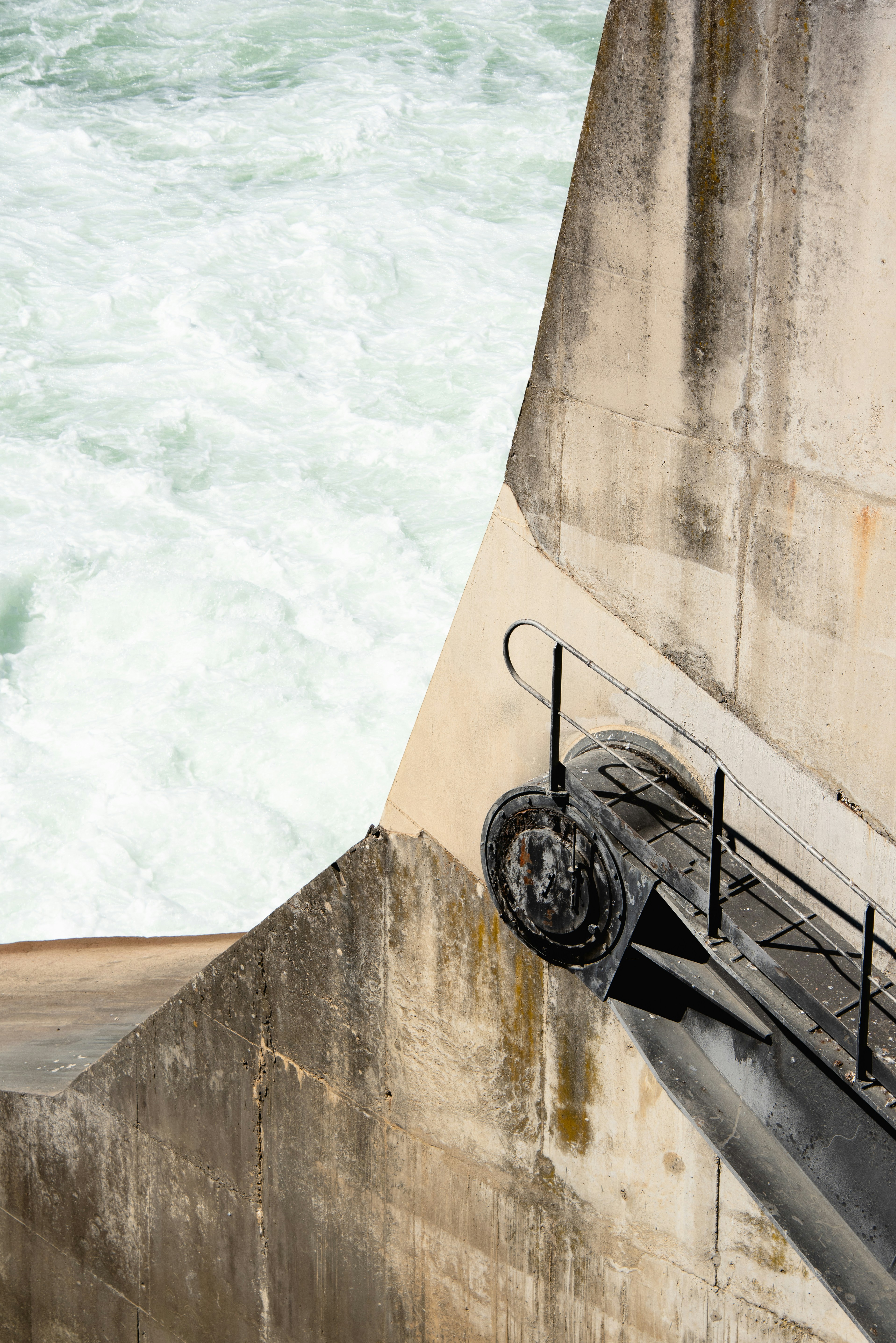 Ice-green surge meets weathered ramp: a seawall ascent into the churning light