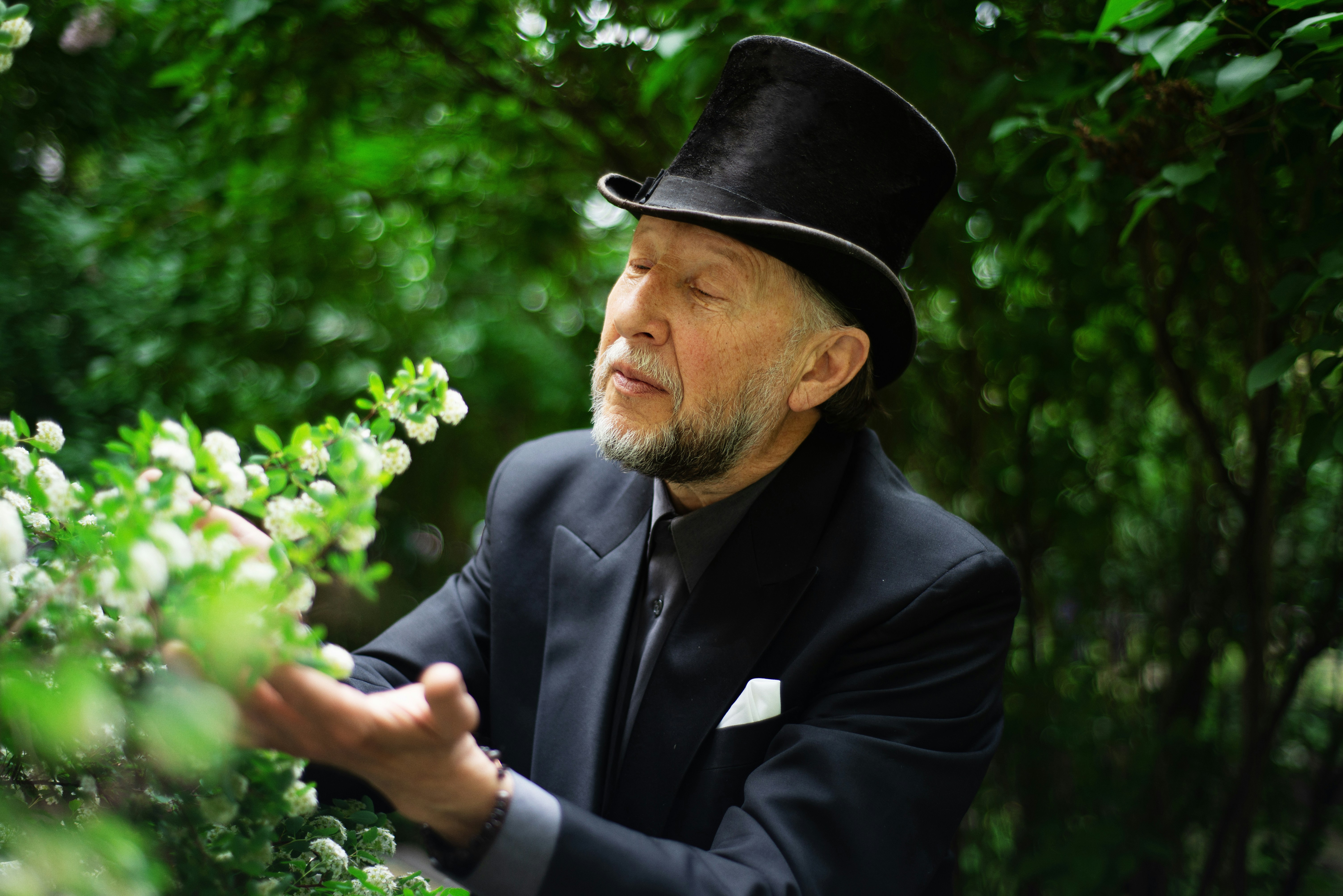 Gentleman in a Black Suit Tends Blossoms Under a Garden Canopy