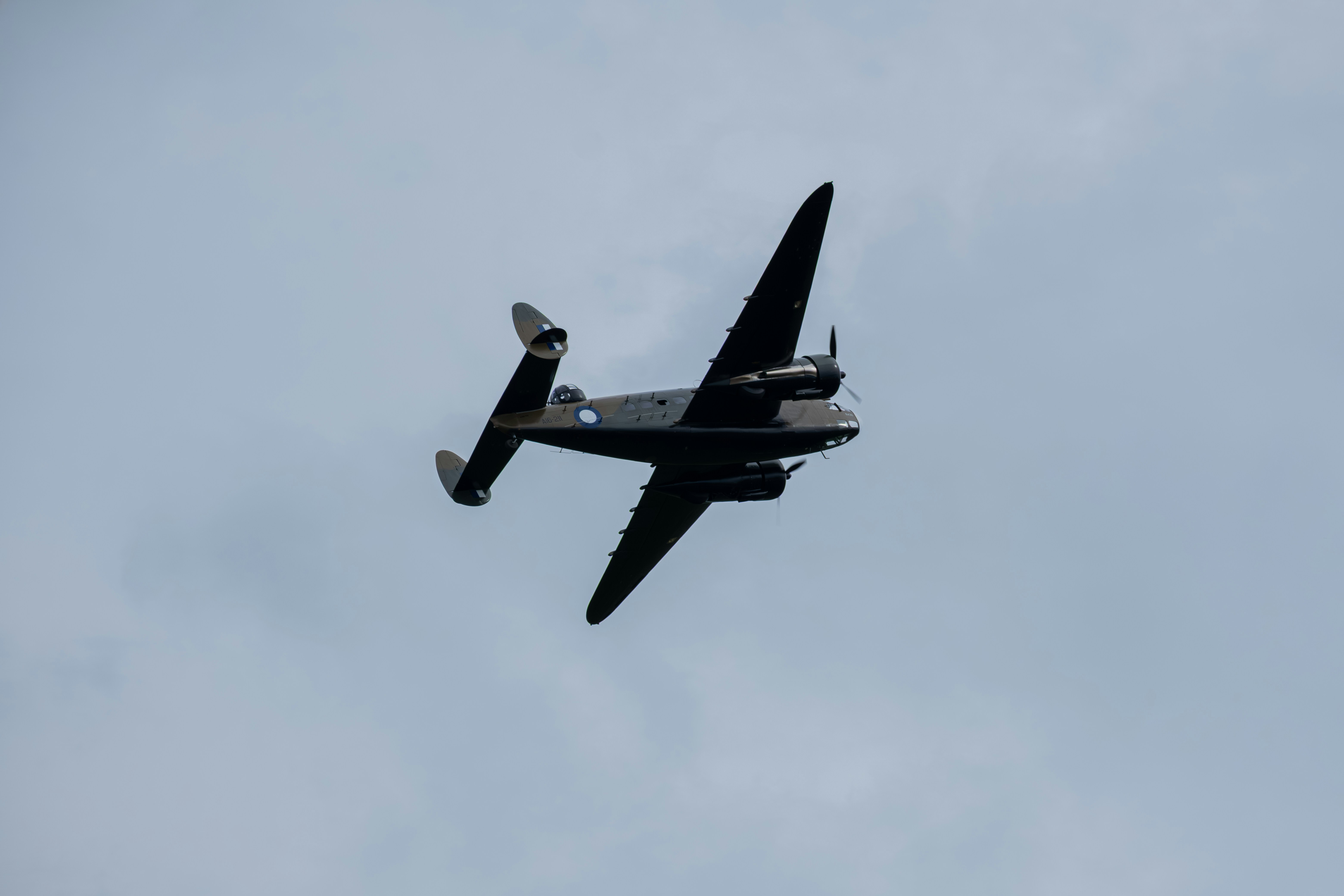 Mid‑Flight Shadow: A vintage aircraft carving a thin arc through a pale sky